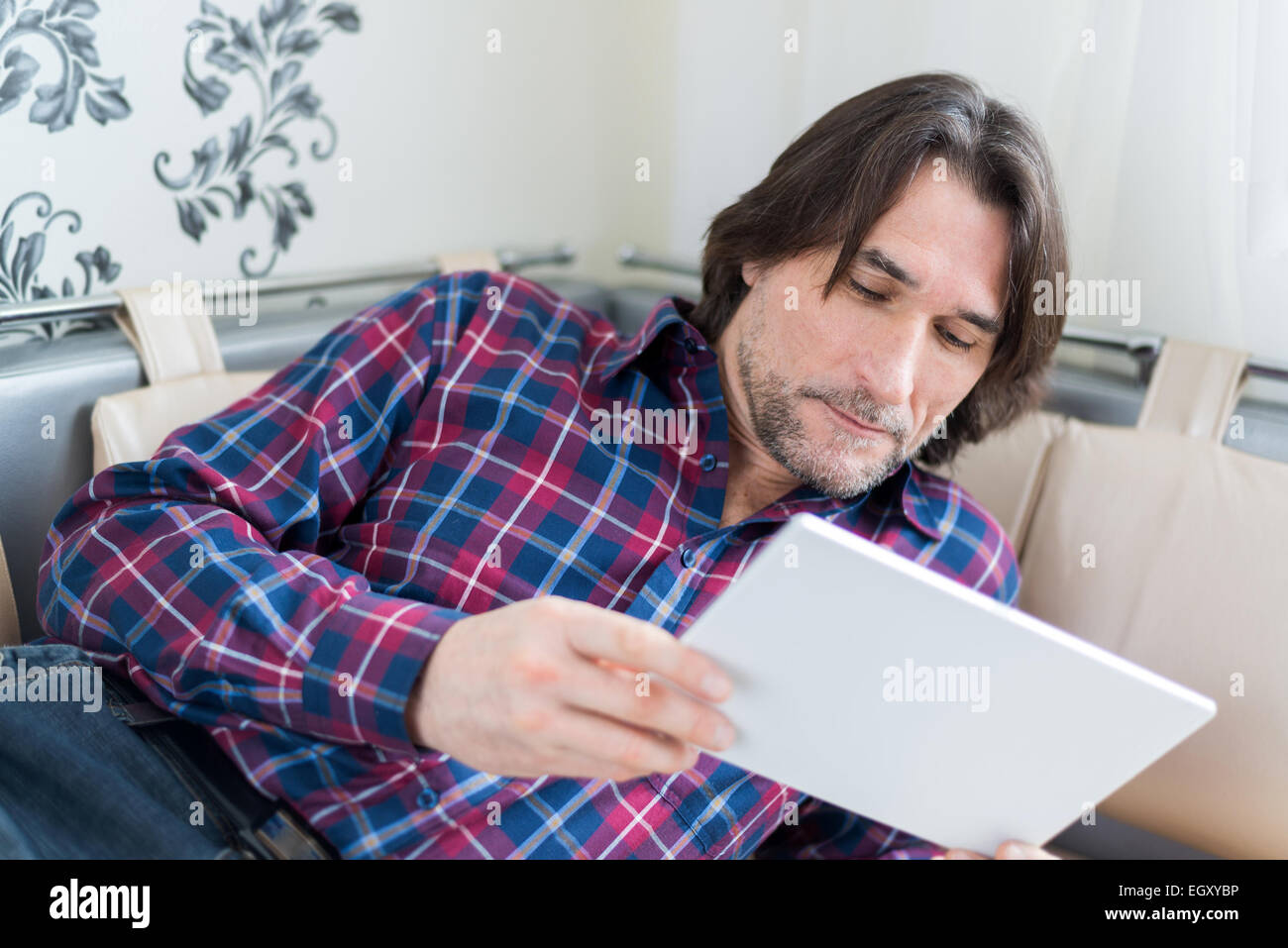 Man sitting in sofa using electronic tablet Stock Photo - Alamy