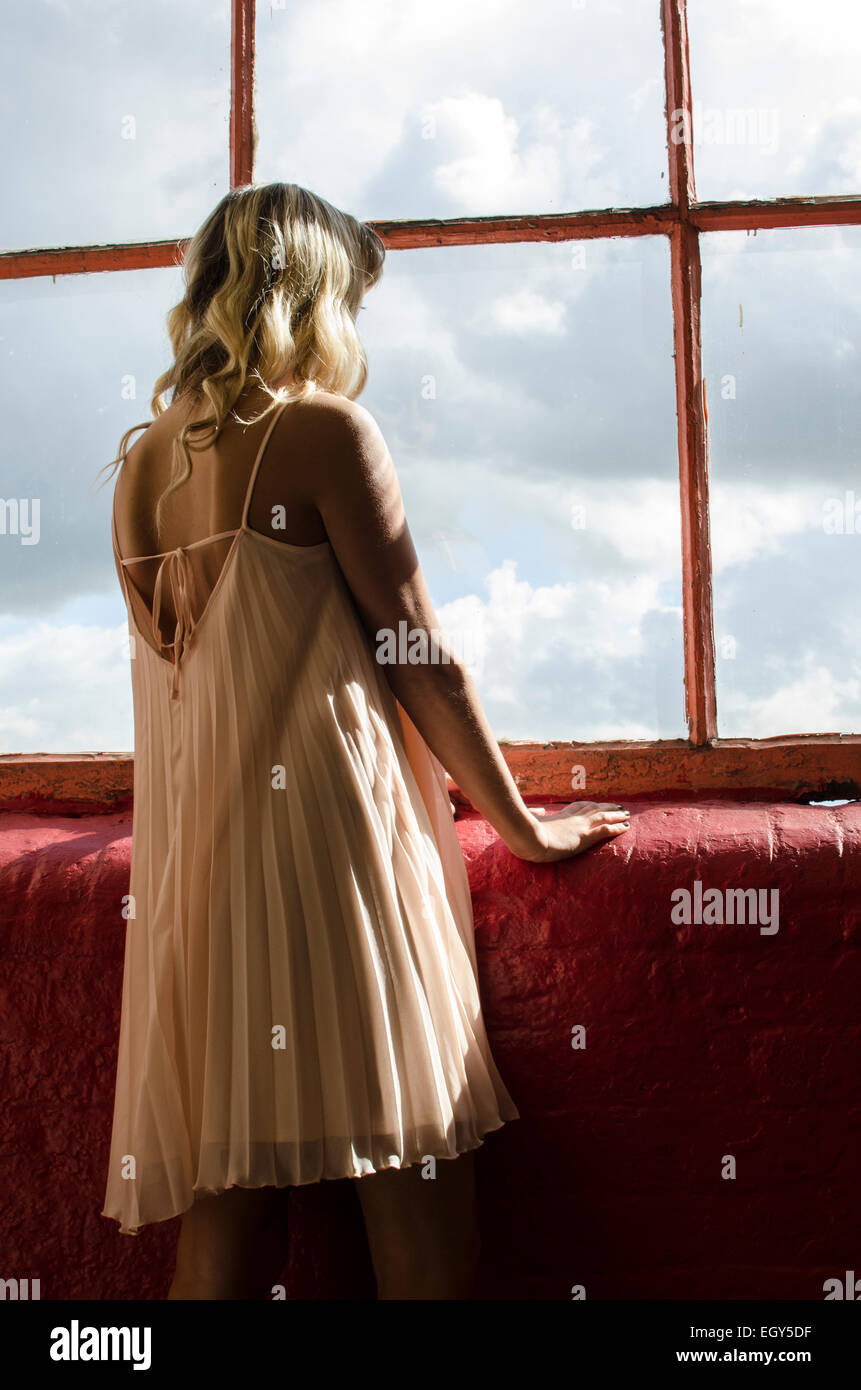 Young woman looking out of the window Stock Photo - Alamy