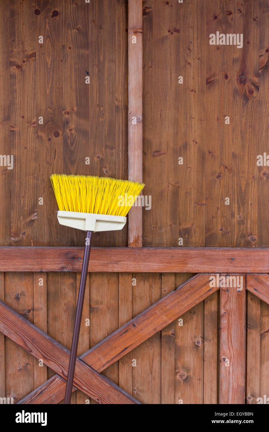 Broom leaning at wooden wall Stock Photo - Alamy