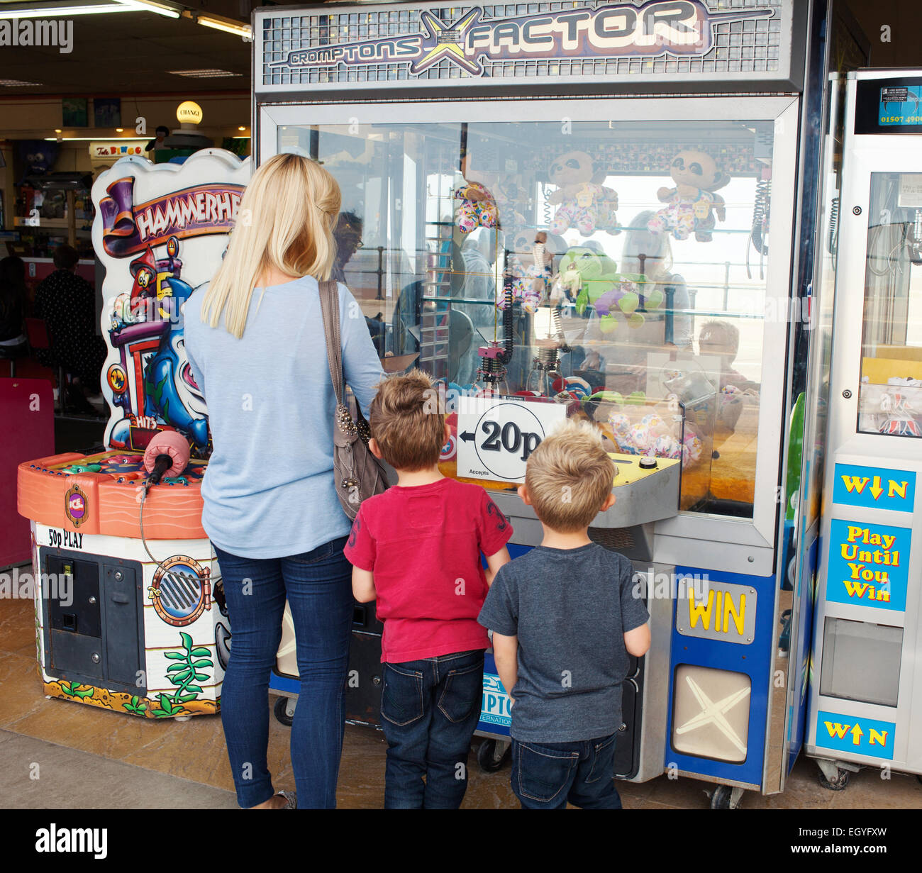 mother with 2 boys playing arcade grabber machines Stock Photo - Alamy