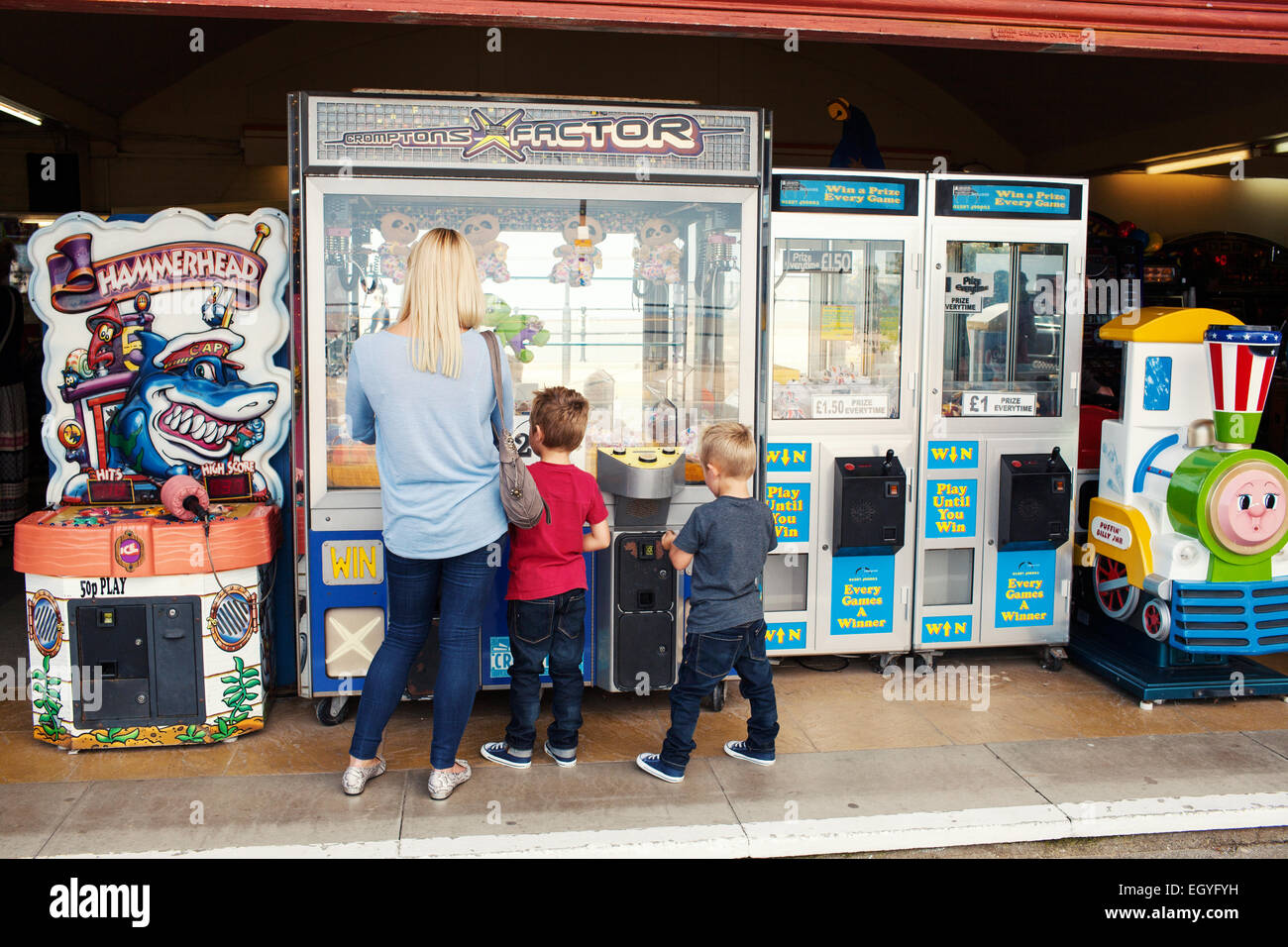 mother with 2 boys playing arcade grabber machines Stock Photo - Alamy