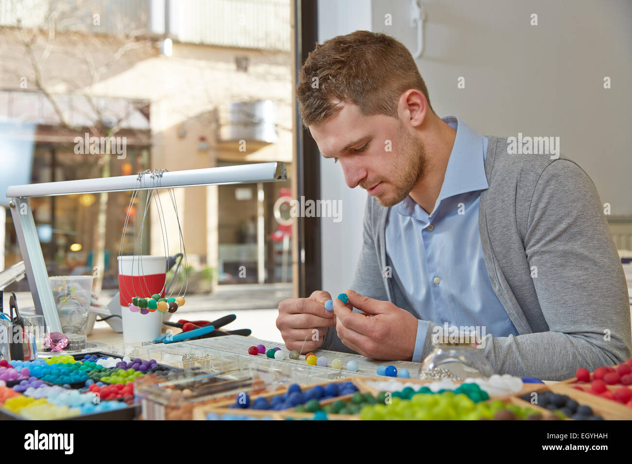 Man working as artisan in jewelry workshop creating a necklace Stock ...