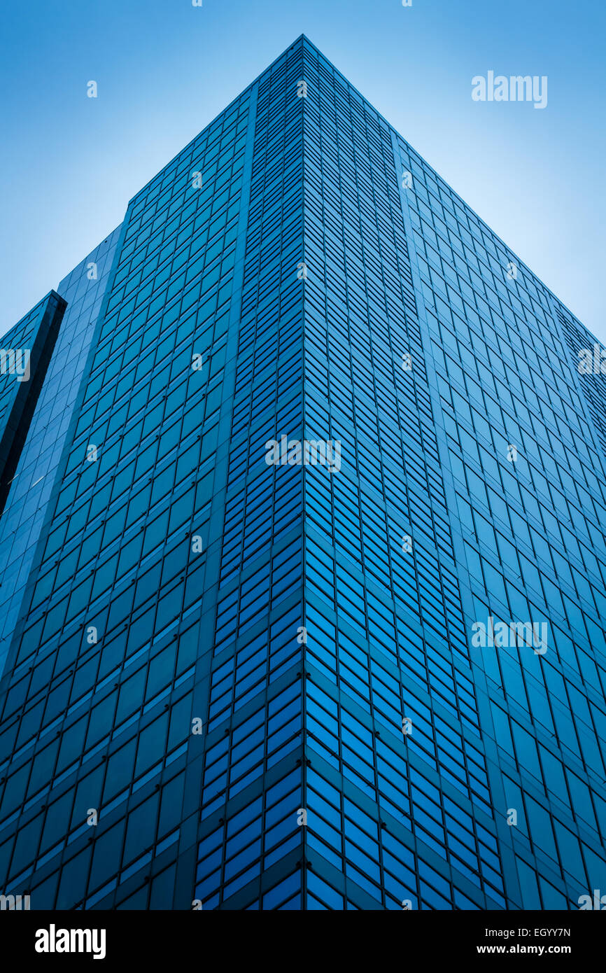 A tall skyscraper reaches to the sky. It's many windows reflecting the ...