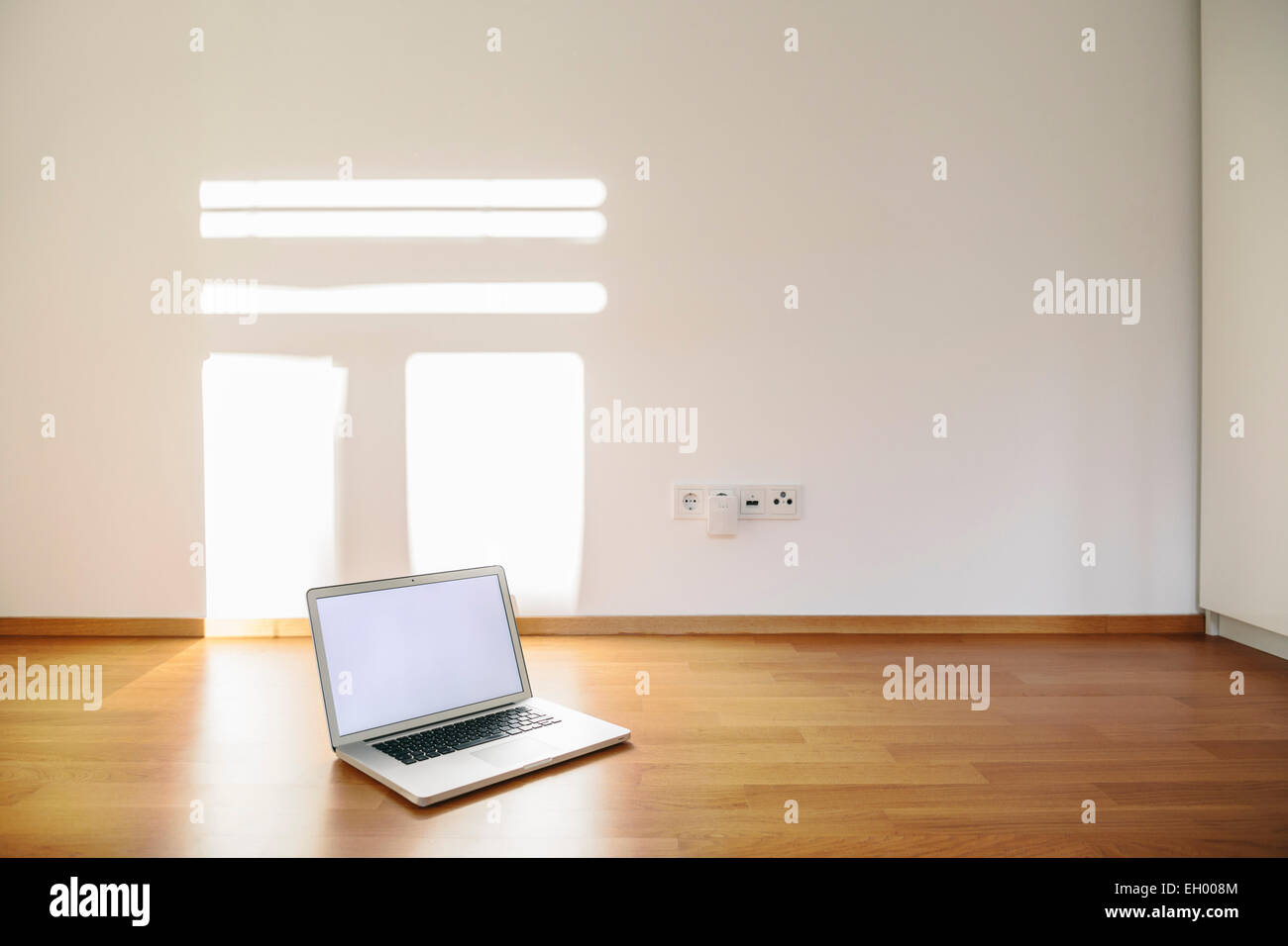 Laptop standing on wooden flooring in an empty room Stock Photo - Alamy
