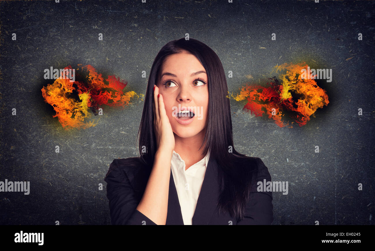 Surprised woman with fire from ears. Concrete gray wall as backdrop ...