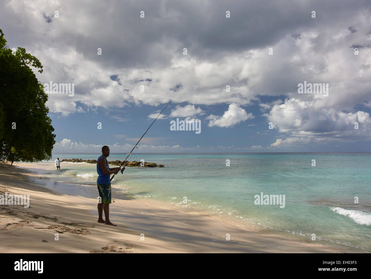 Barbados beach. Man (Caribbean) fishing from the beach using rod and ...