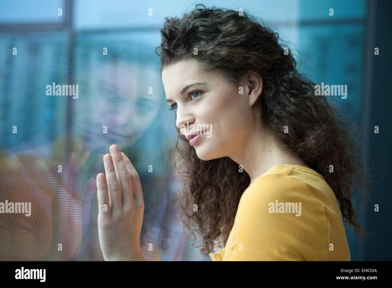 Smiling young woman looking out of window Stock Photo - Alamy