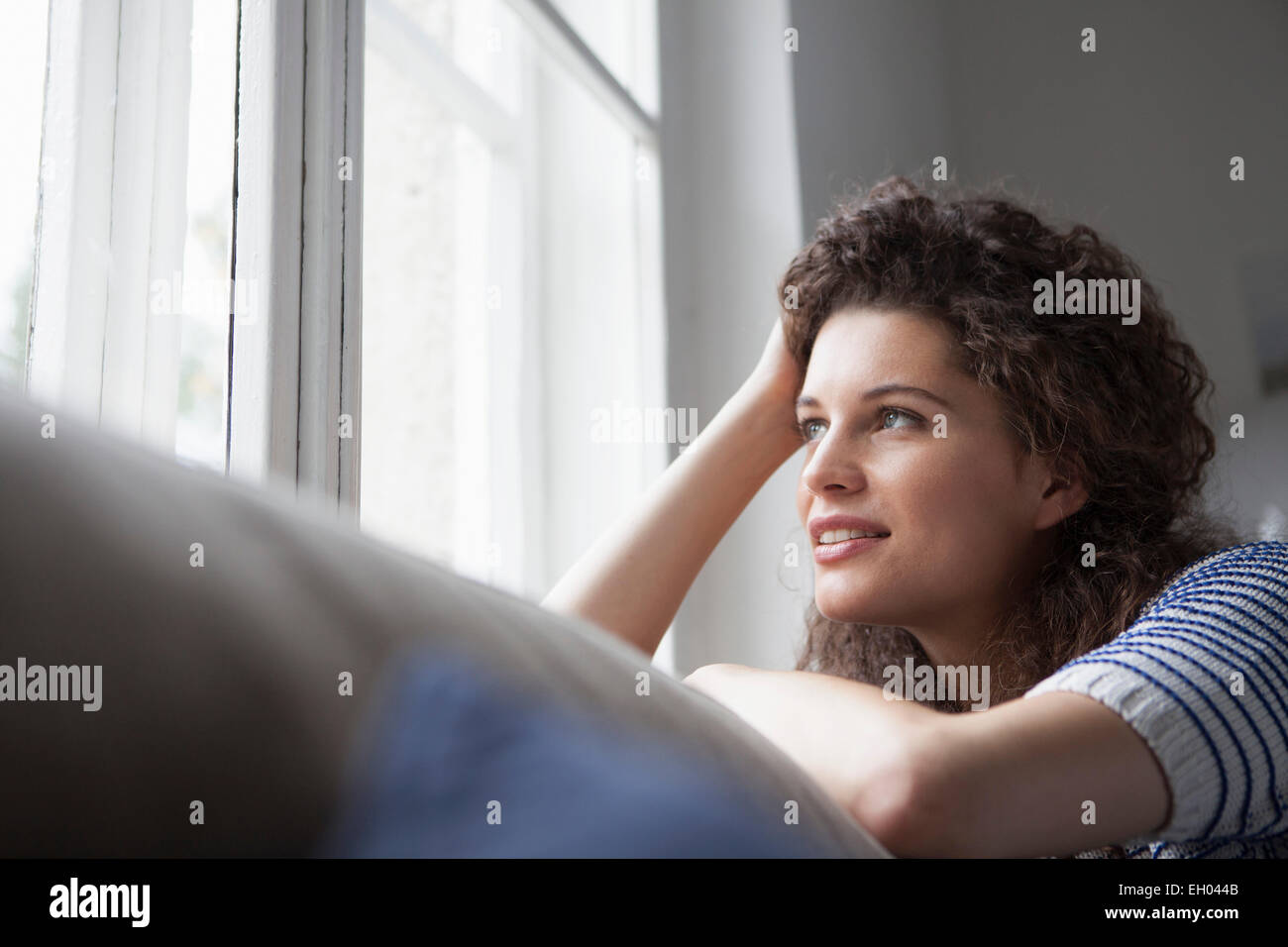 Young woman at home looking out of window Stock Photo - Alamy