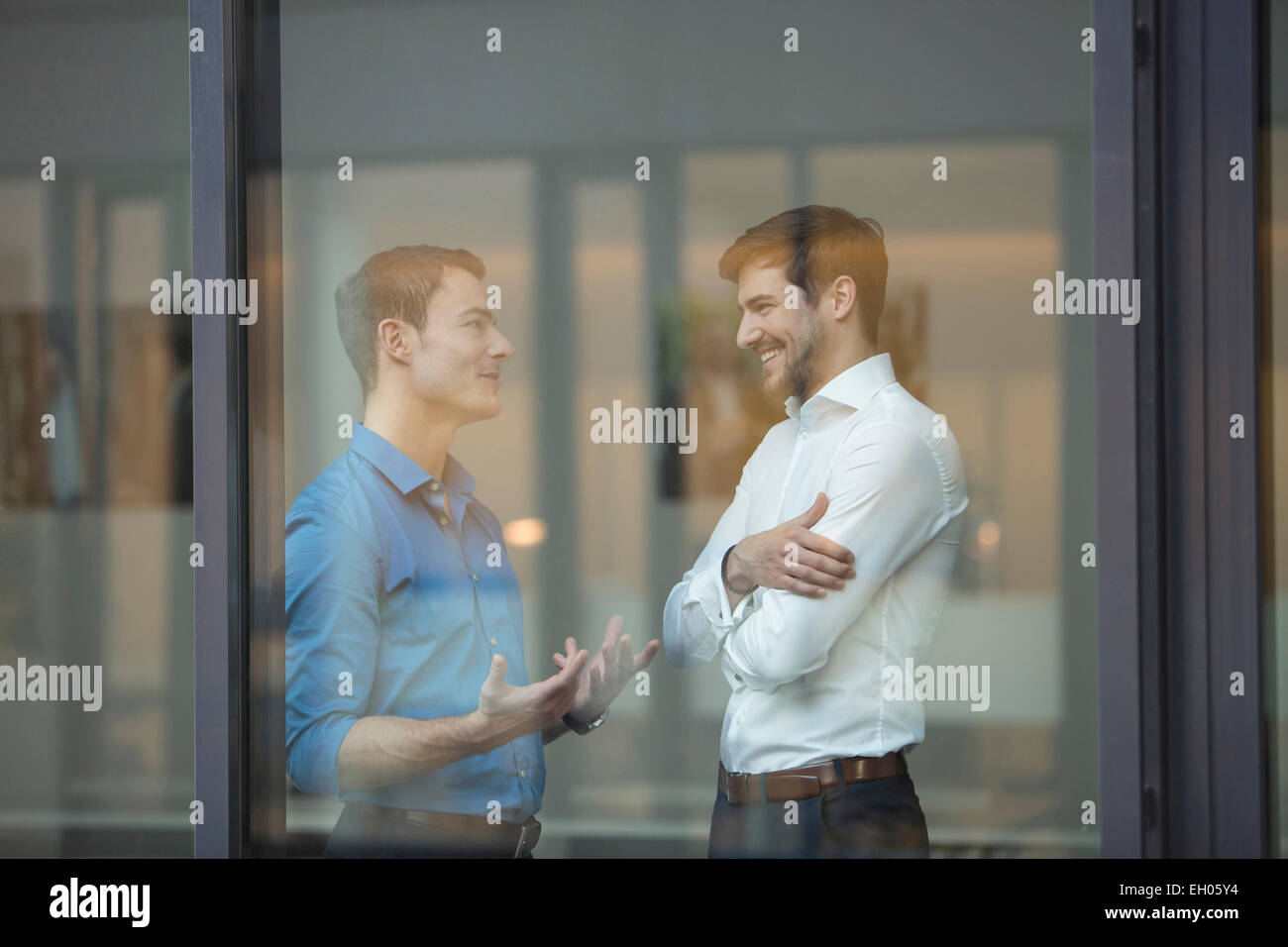 Two businessmen communicating behind window in an office Stock Photo ...