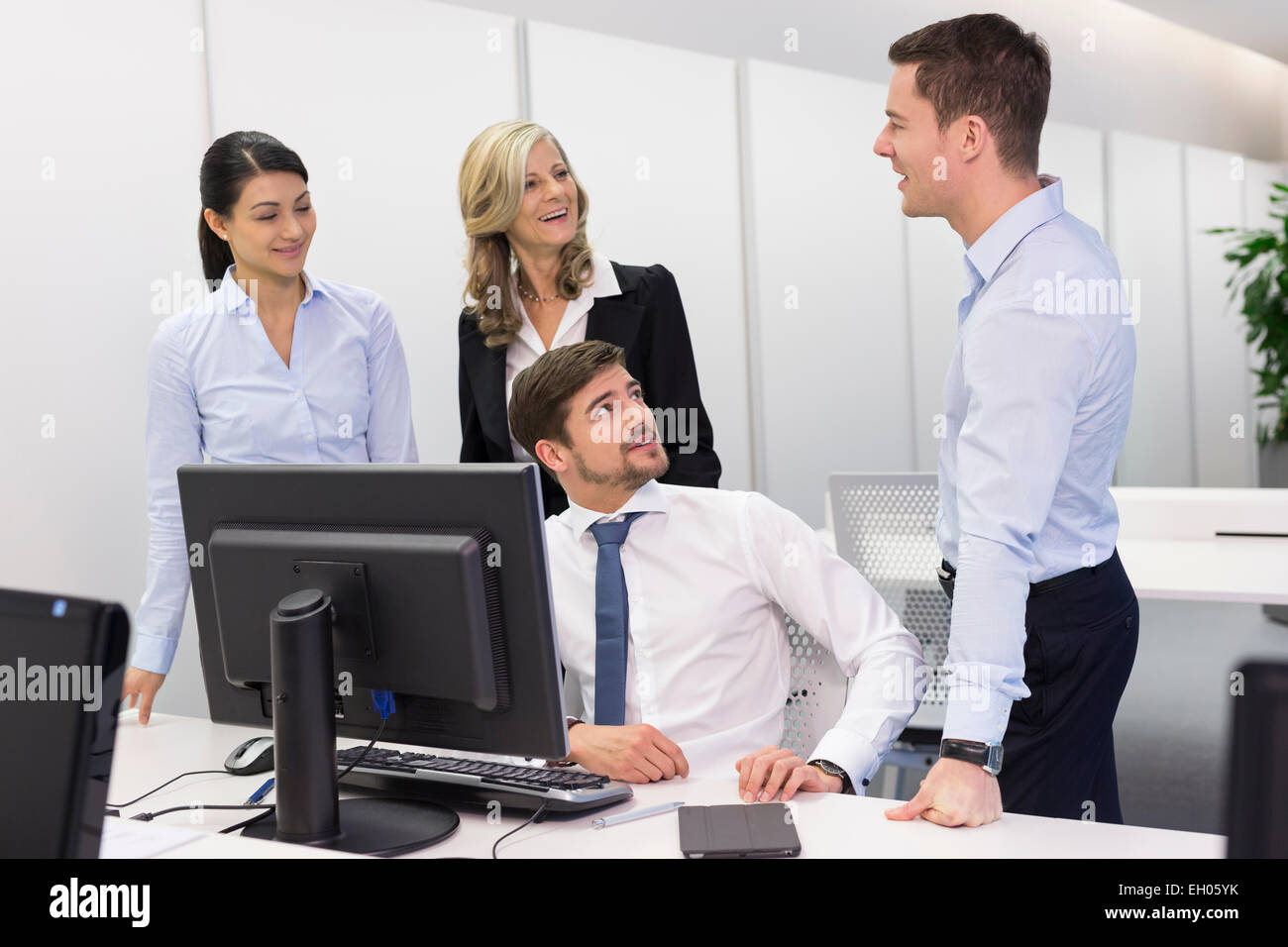 Businesspeople talking at desk in office Stock Photo - Alamy