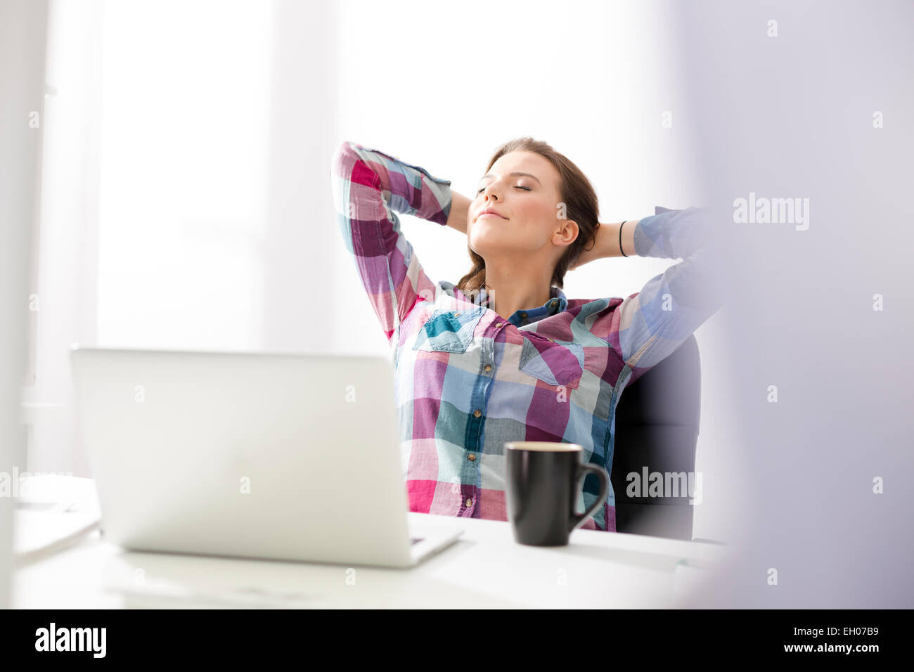 Young woman at desk leaning back Stock Photo - Alamy
