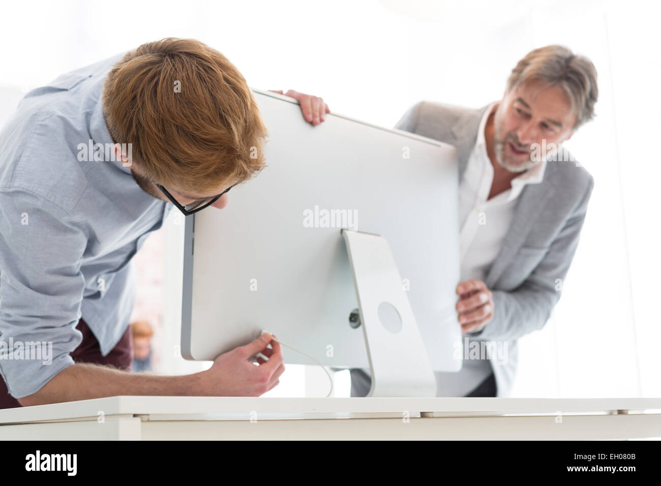 Two men in office connecting computer screen Stock Photo - Alamy