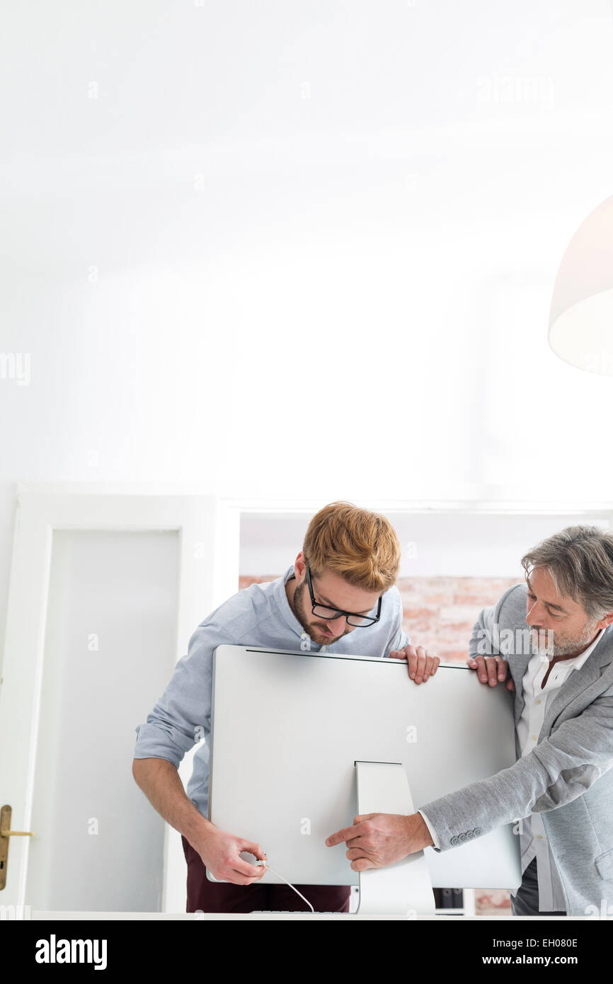 Two men in office connecting computer screen Stock Photo - Alamy