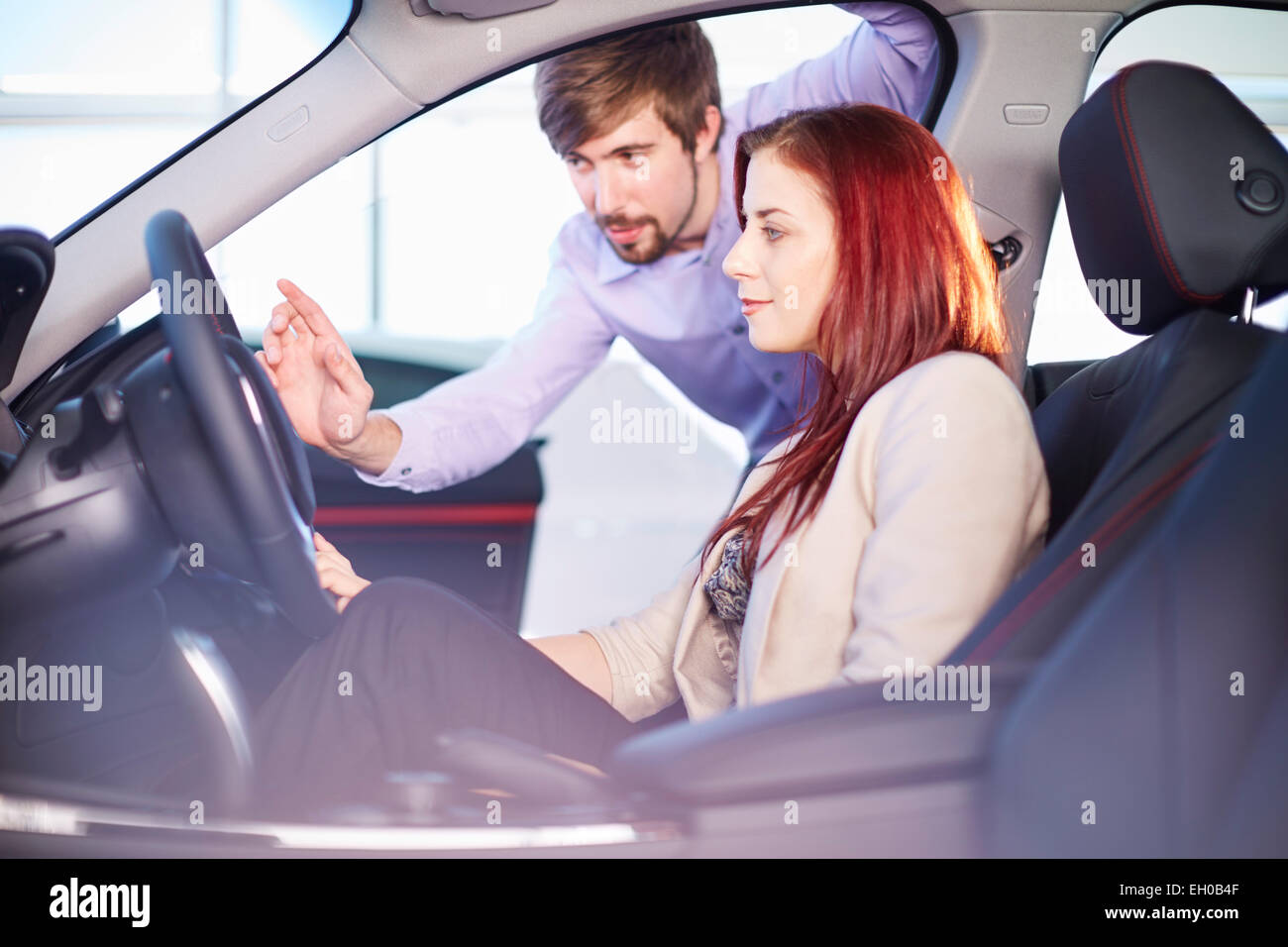 Car dealer talking to client inside car Stock Photo - Alamy