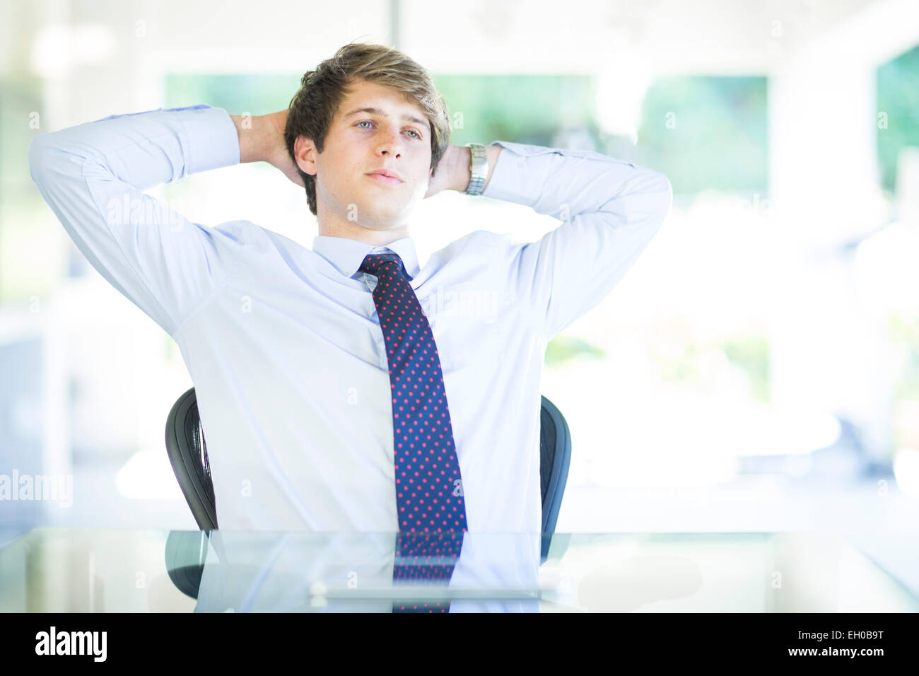 Young businessman in office leaning back Stock Photo - Alamy