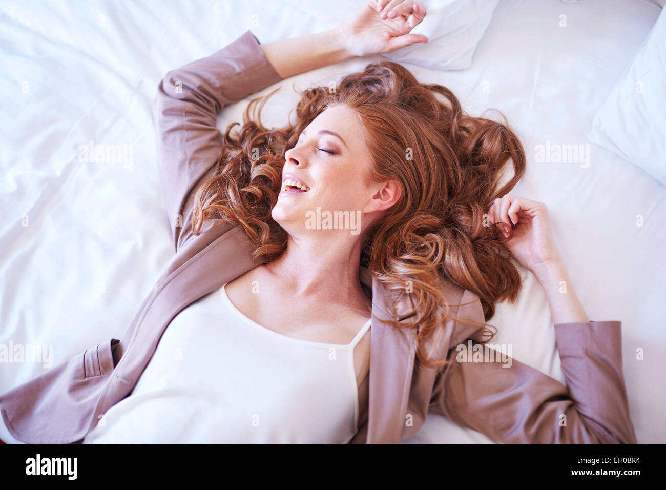 Happy woman lying on hotel bed Stock Photo - Alamy