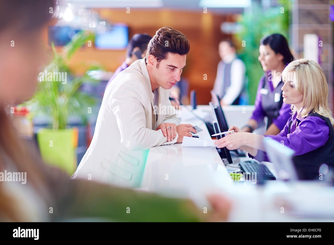 Businessman registering at hotel reception Stock Photo - Alamy
