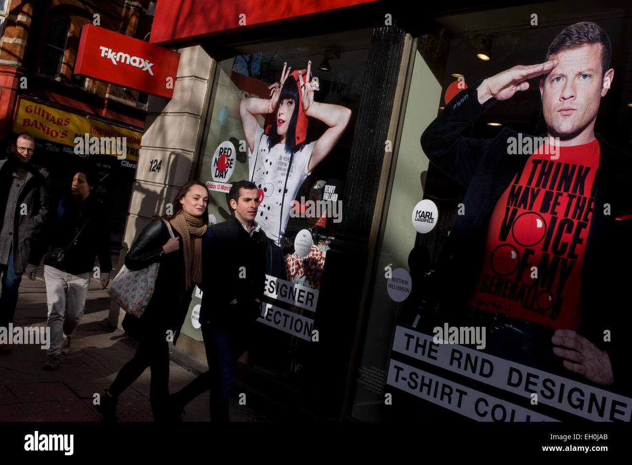 Shoppers walk beneath TK Maxx shop posters for the Red Nose Day charity ...