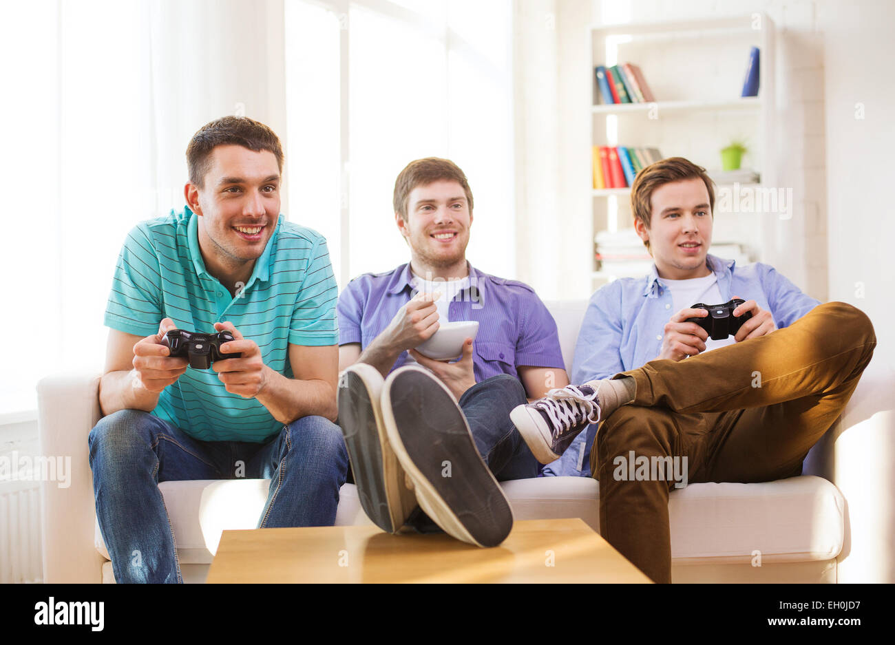 smiling friends playing video games at home Stock Photo - Alamy