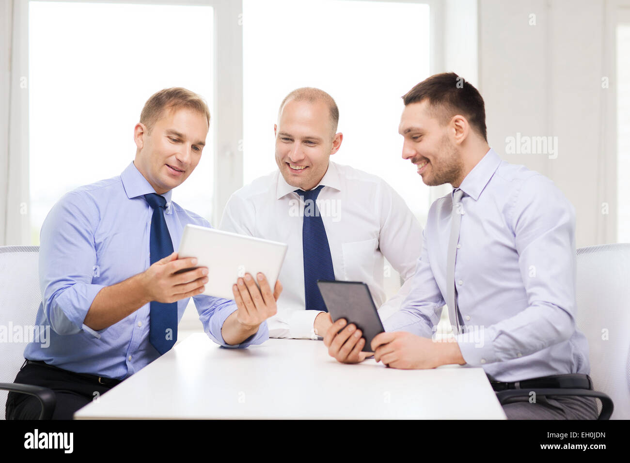 three smiling businessmen with tablet pc in office Stock Photo - Alamy