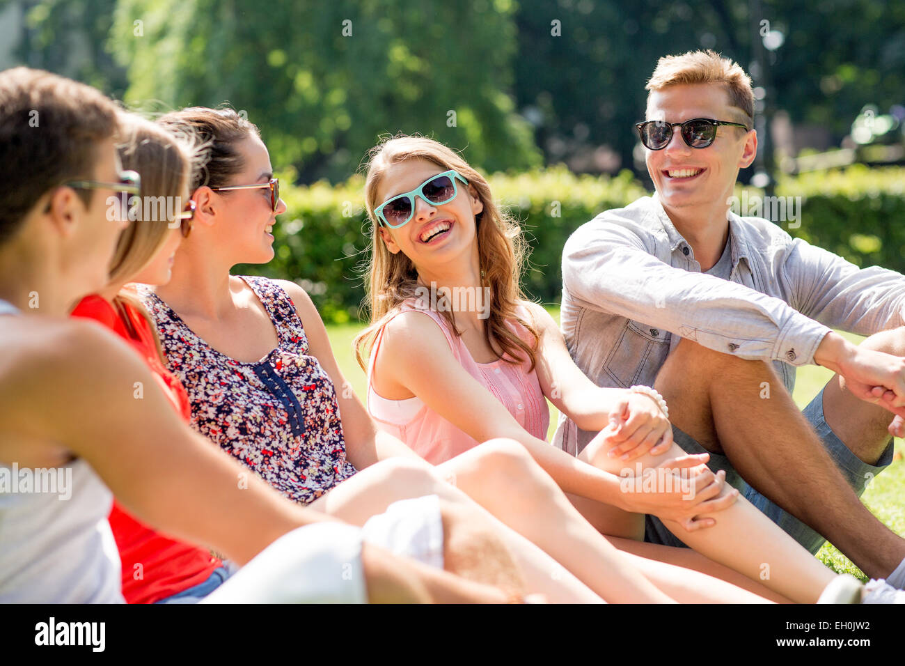 group of smiling friends outdoors sitting in park Stock Photo - Alamy