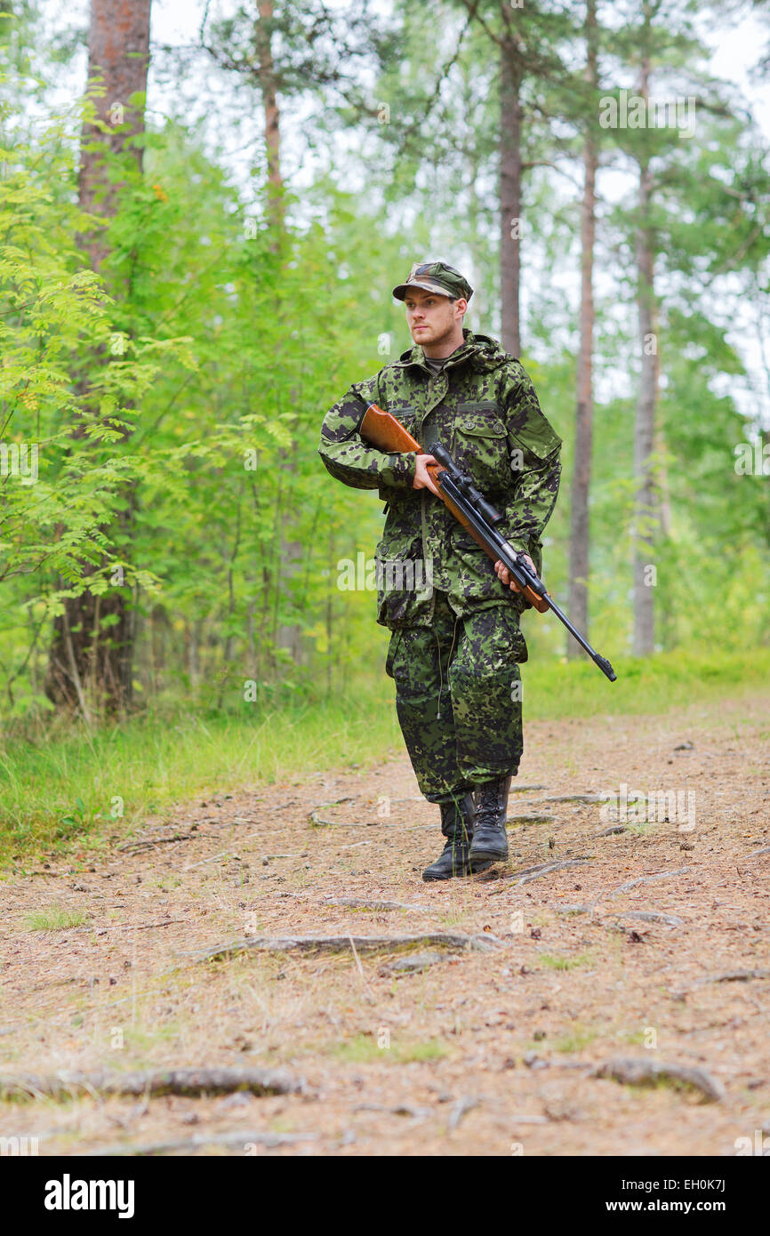 young soldier or hunter with gun in forest Stock Photo - Alamy