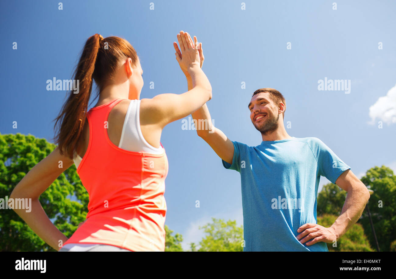 two smiling people making high five outdoors Stock Photo - Alamy