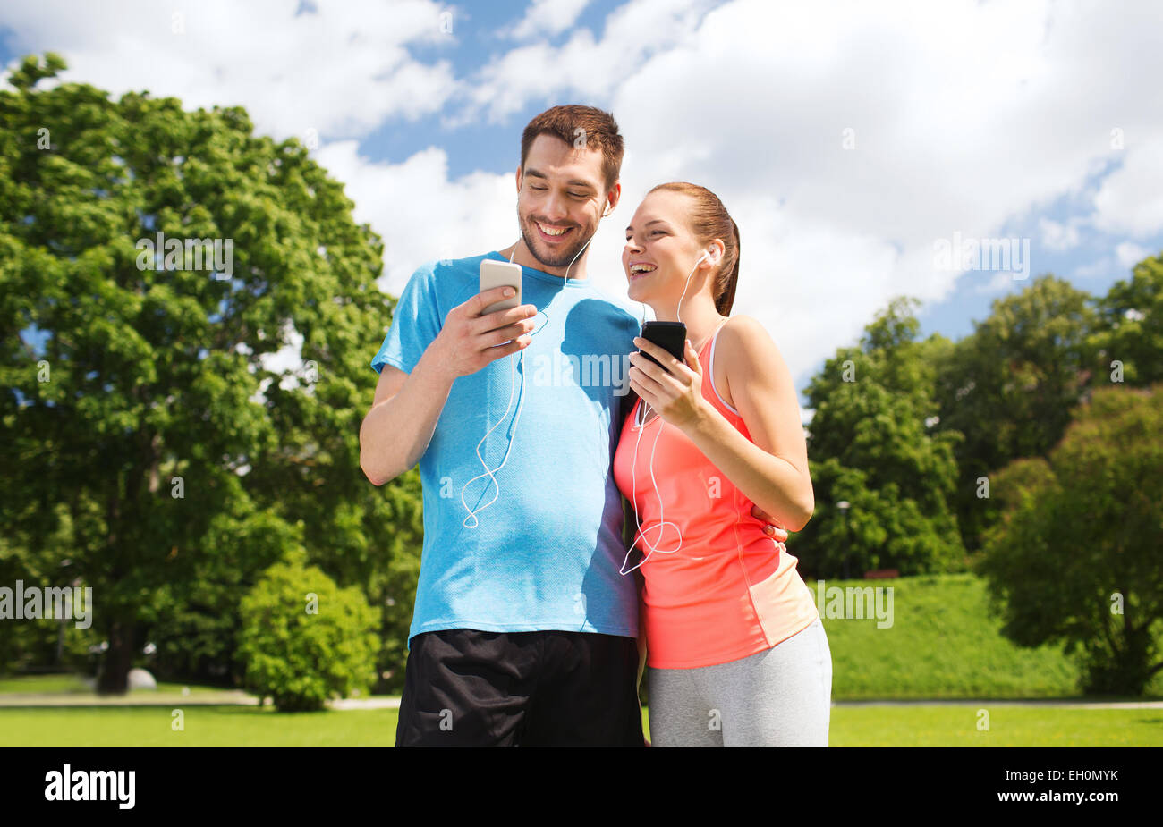 two smiling people with smartphones outdoors Stock Photo - Alamy