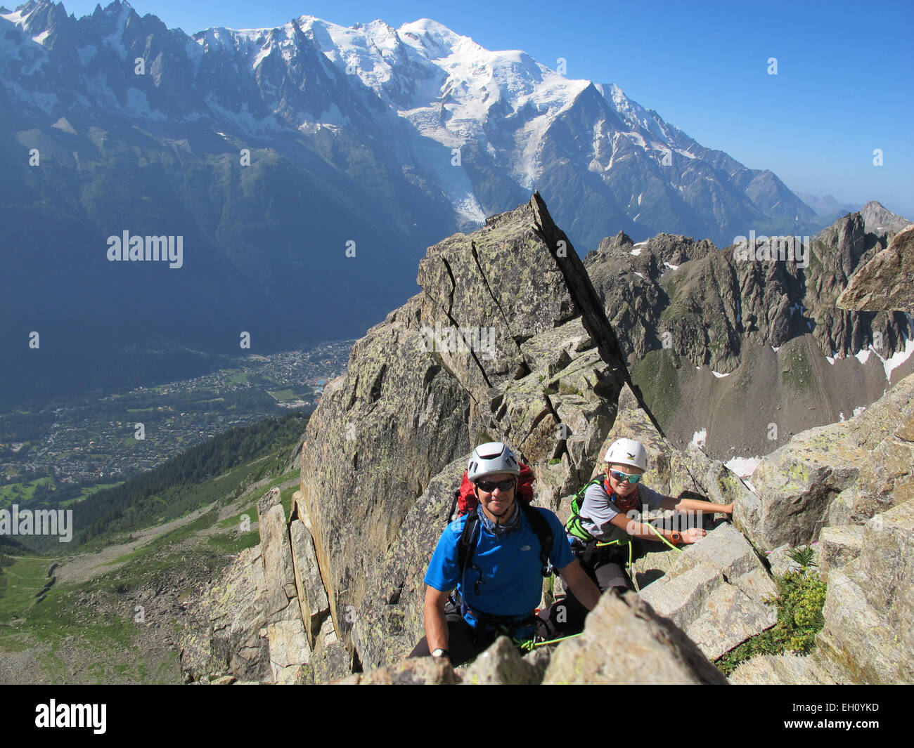Boy and father rock climbing on a sunny day in the alps. Mont Blanc is ...