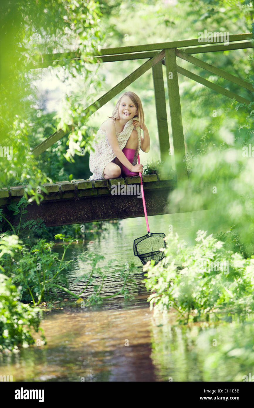 Young Girl Catching Fish With Net From Wooden Bridge Stock Photo - Alamy