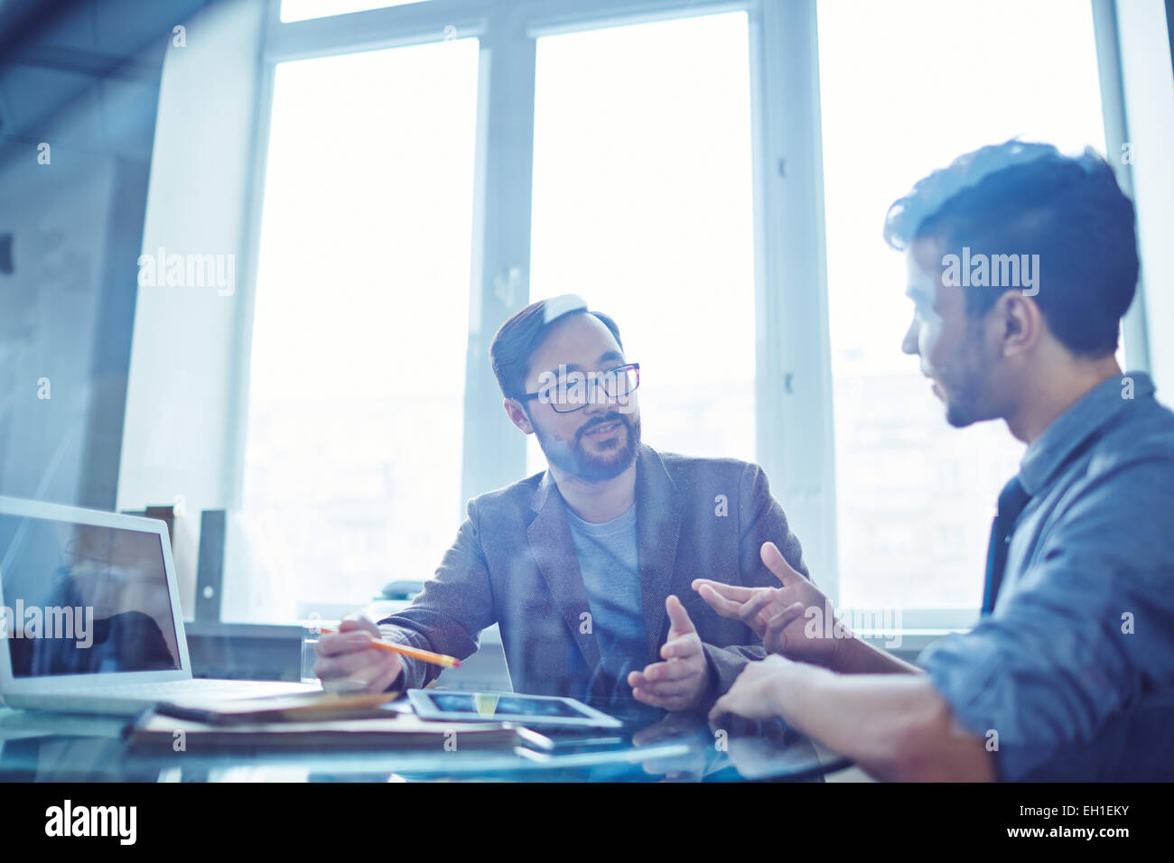 Male colleagues communicating during work Stock Photo - Alamy