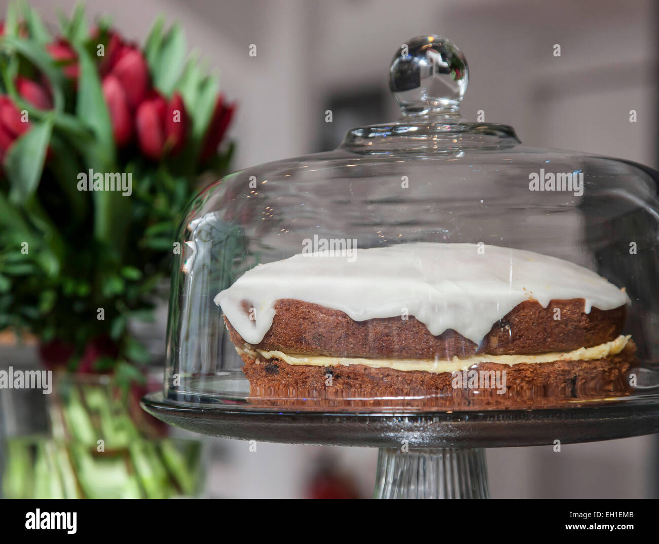 Iced sponge cake on glass cake stand in a café Stock Photo - Alamy