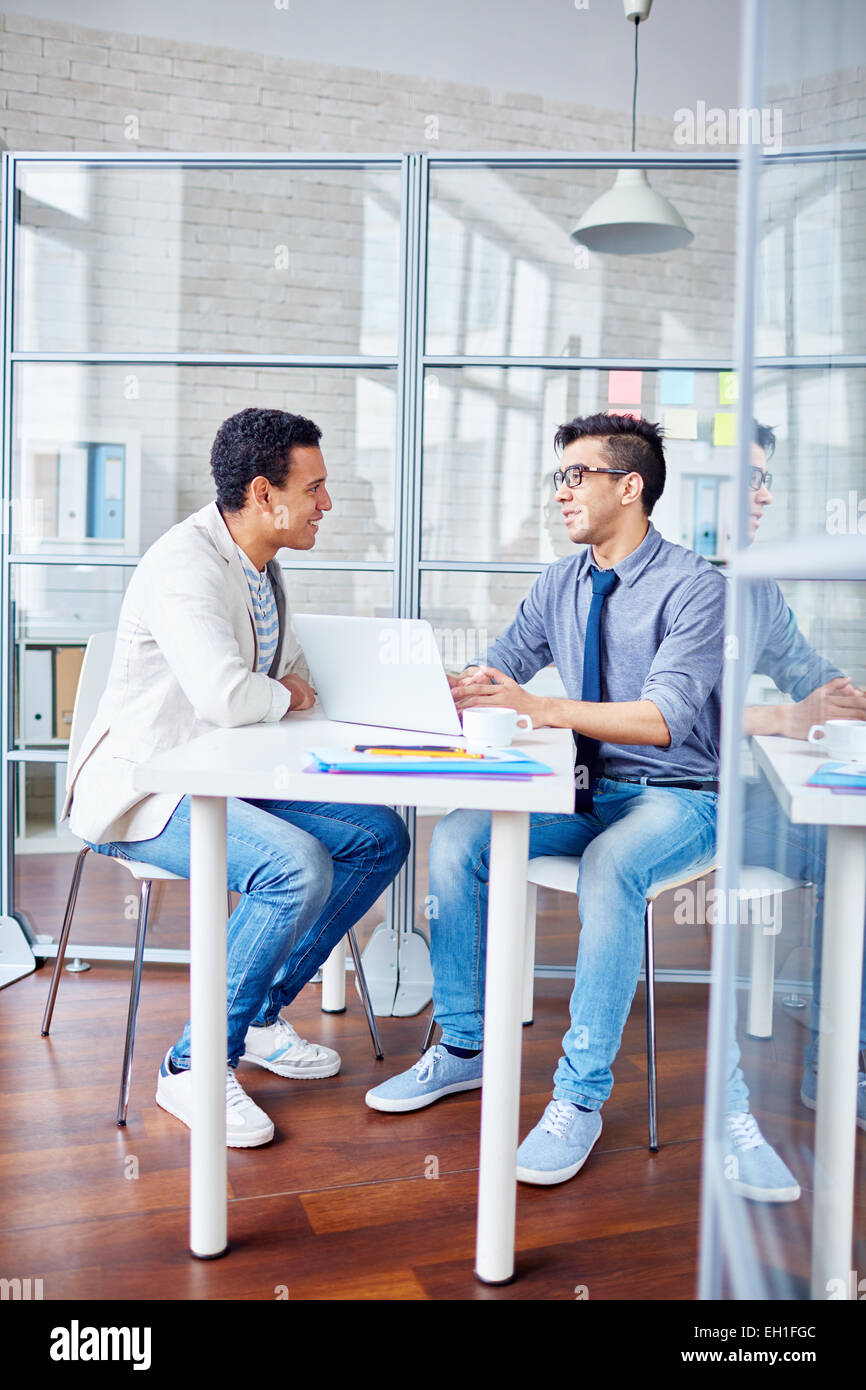 Young man talking to modern guy while hiring him at work Stock Photo ...