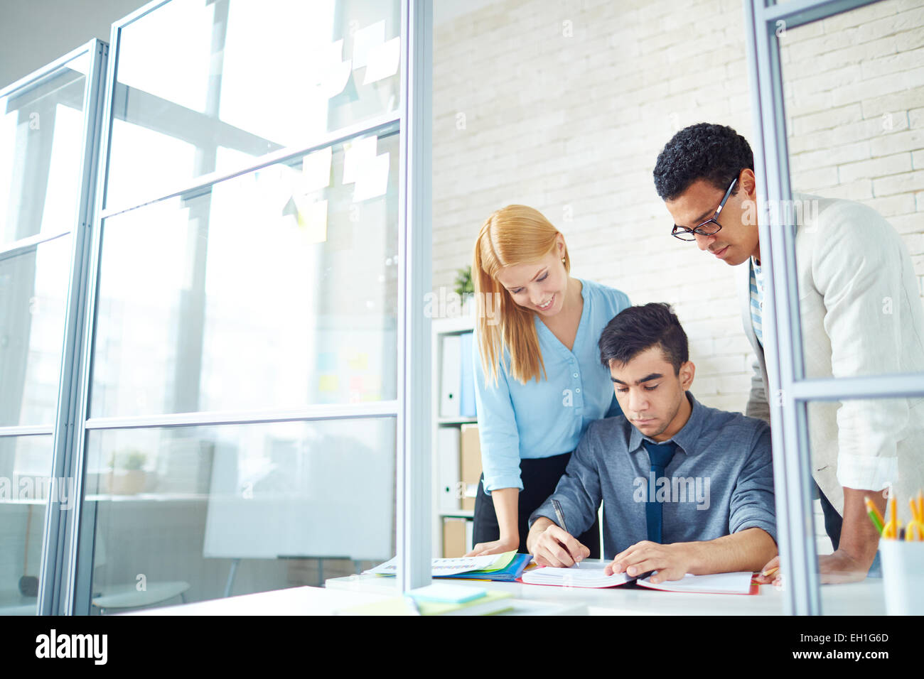 Young employer signing contract with his colleagues near by Stock Photo ...