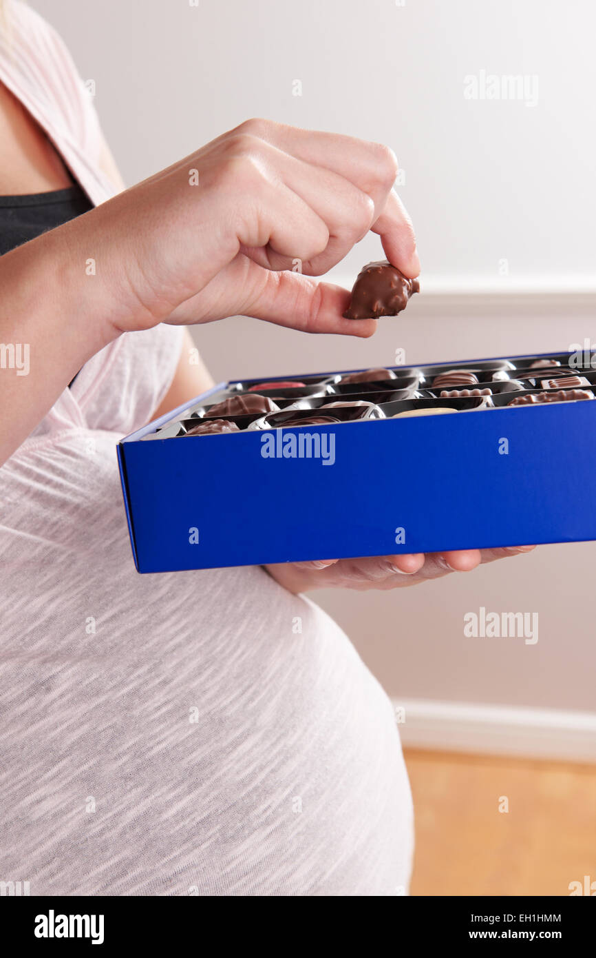Pregnant Woman Eating Box Of Chocolates Stock Photo - Alamy