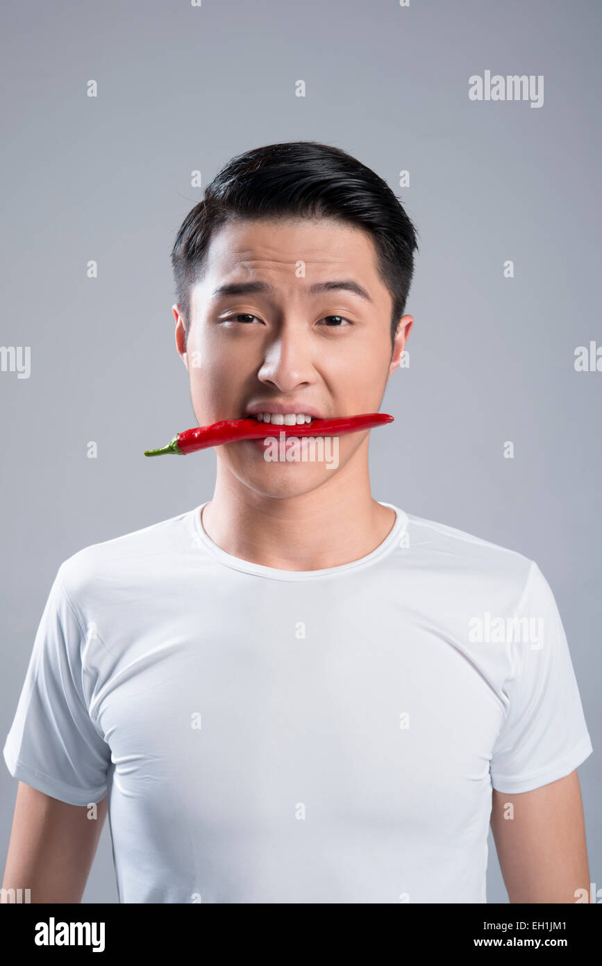 Young man eating pepper Stock Photo - Alamy