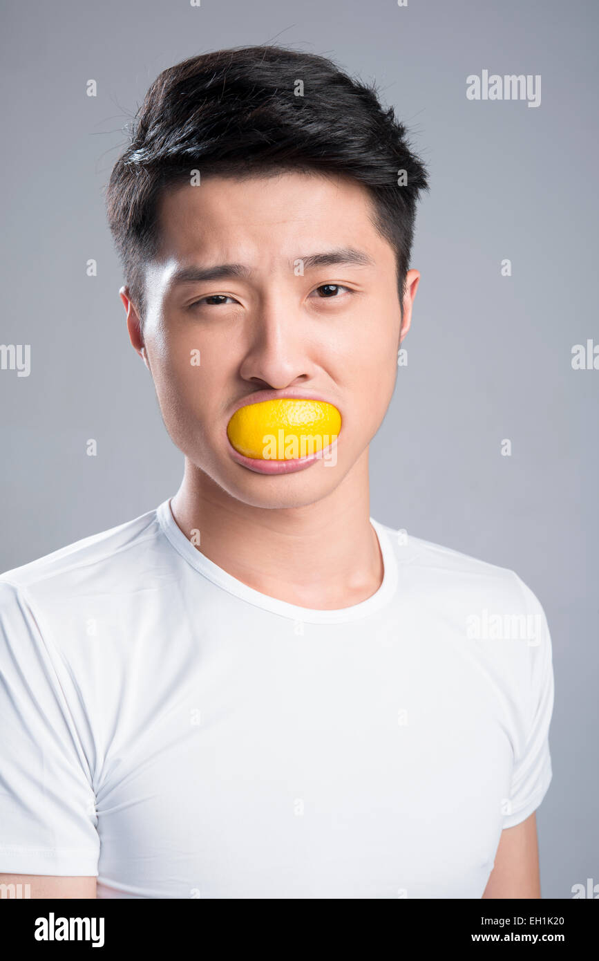 Young man eating lemon Stock Photo - Alamy