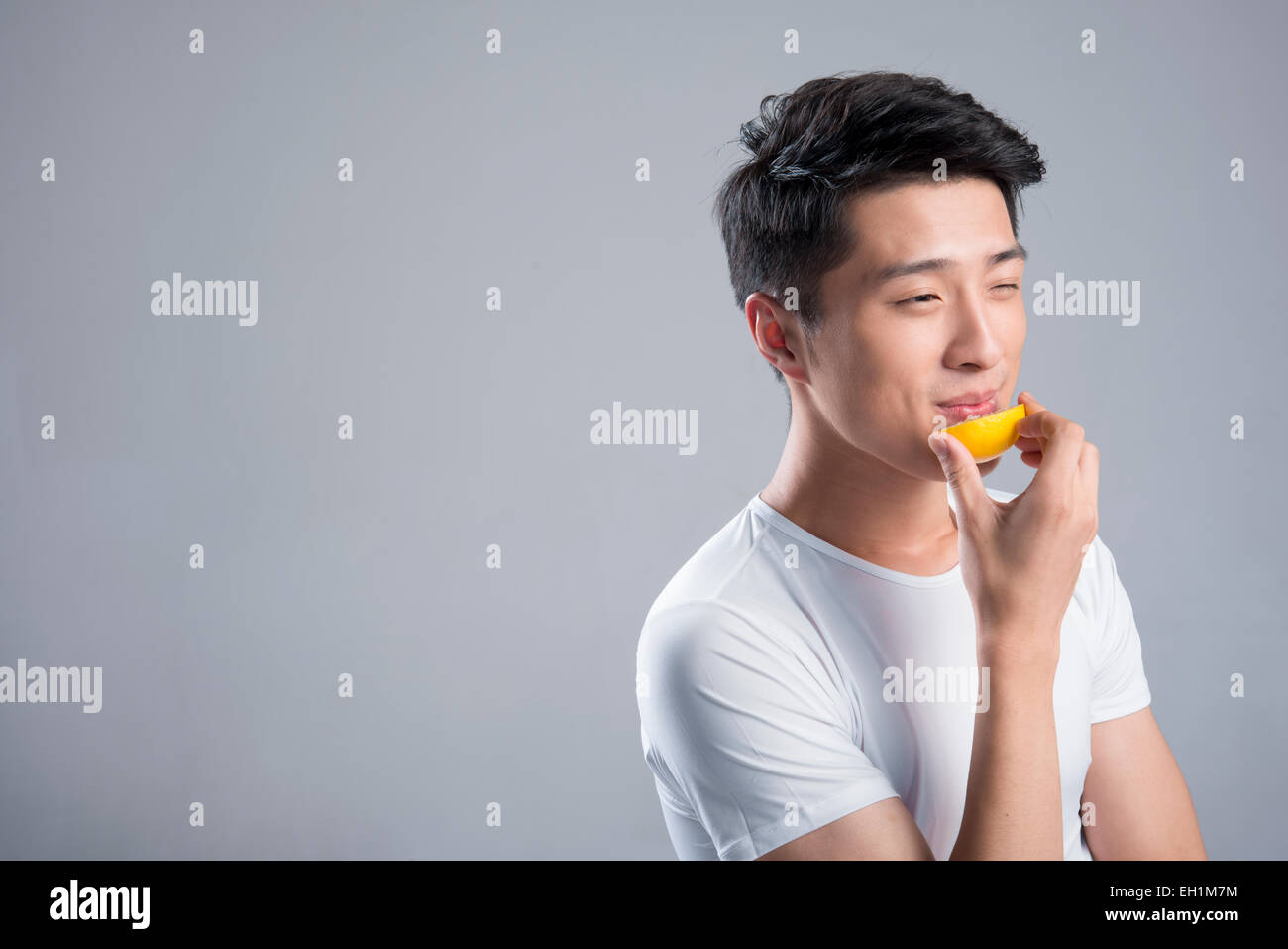 Young man eating lemon Stock Photo - Alamy