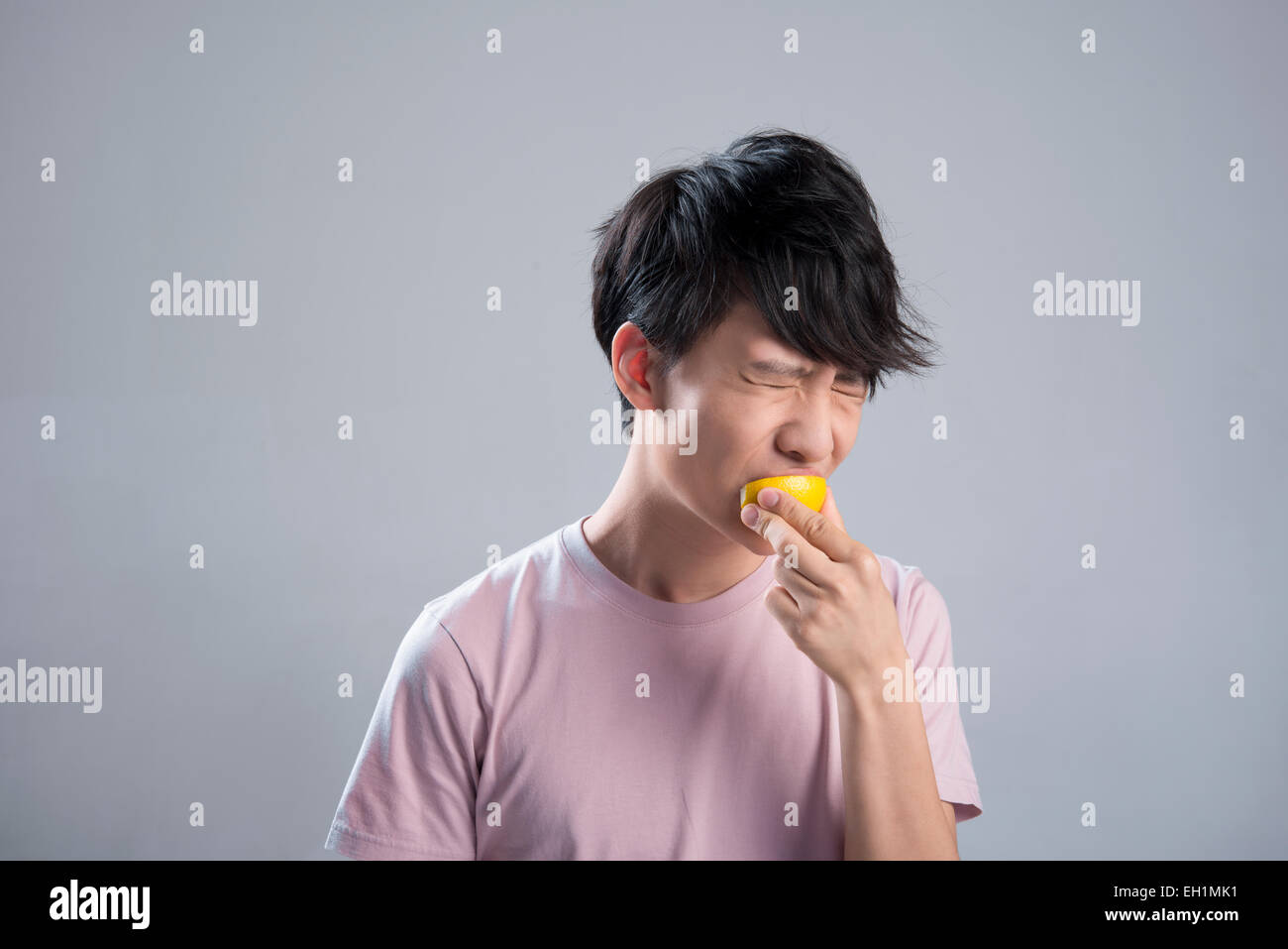 Young man eating lemon Stock Photo - Alamy