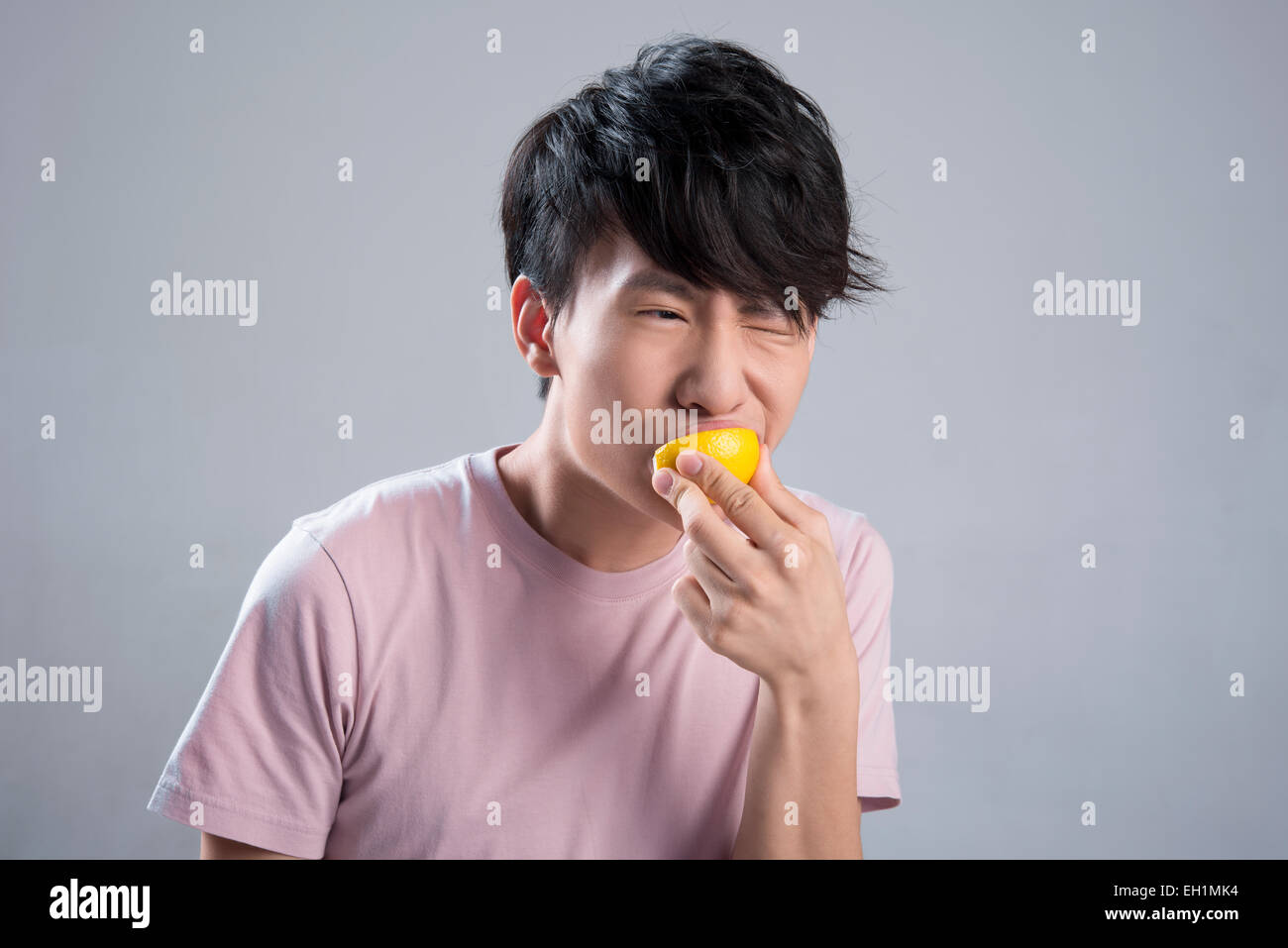 Young man eating lemon Stock Photo - Alamy