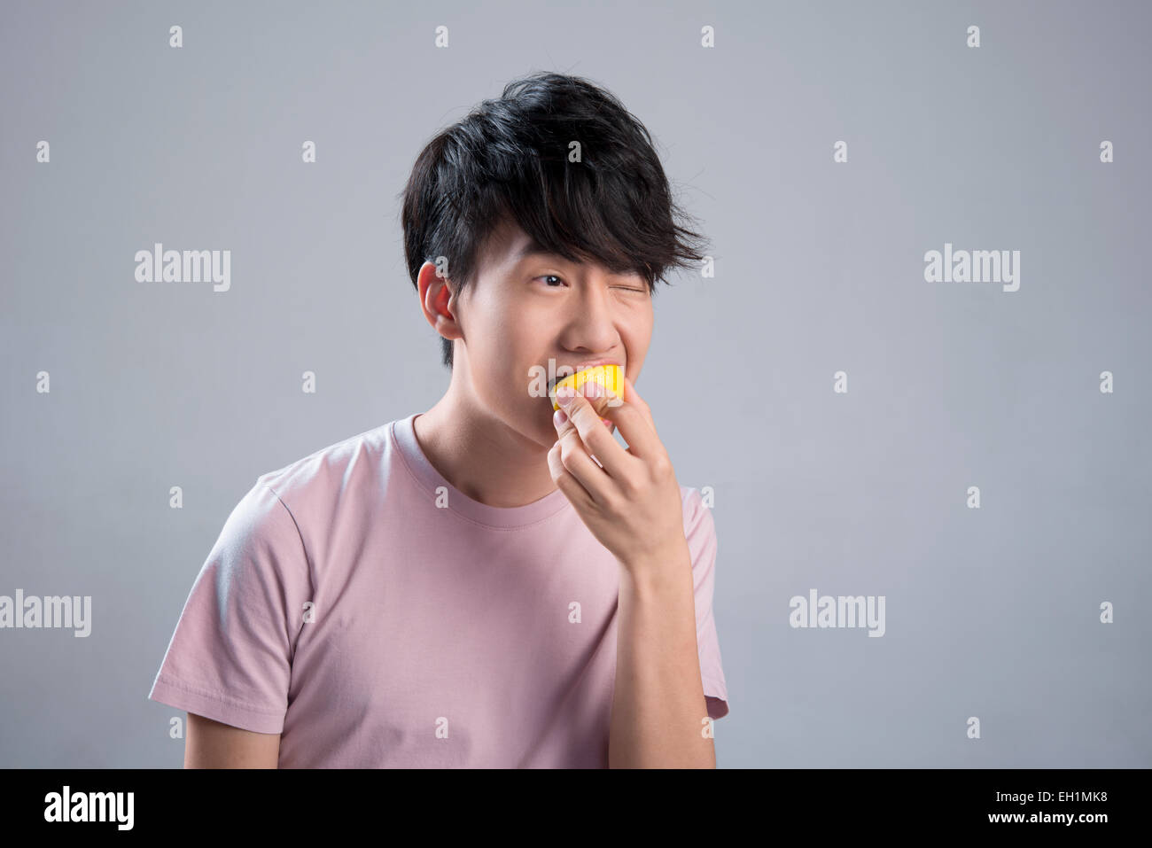 Young man eating lemon Stock Photo - Alamy