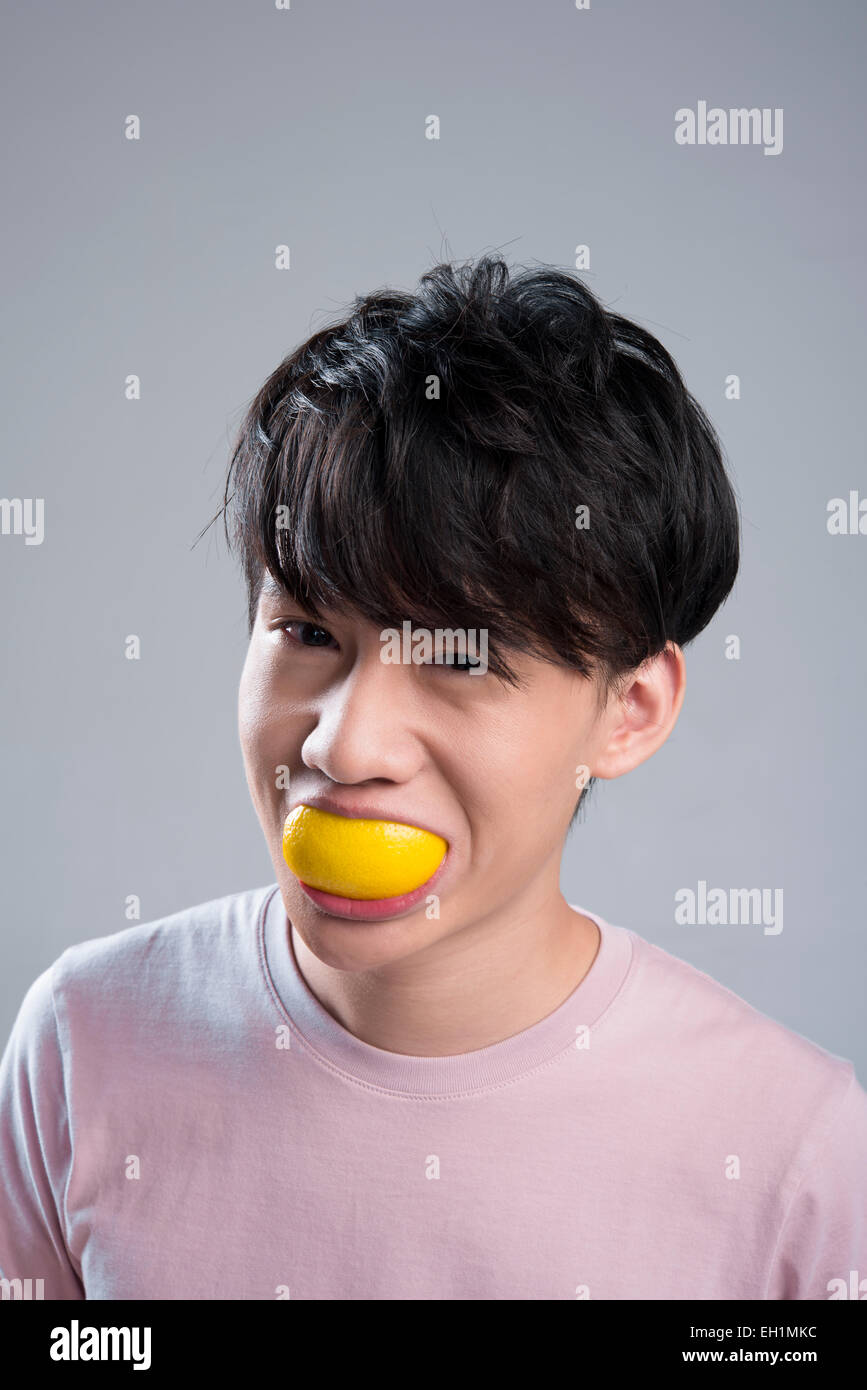 Young man eating lemon Stock Photo - Alamy