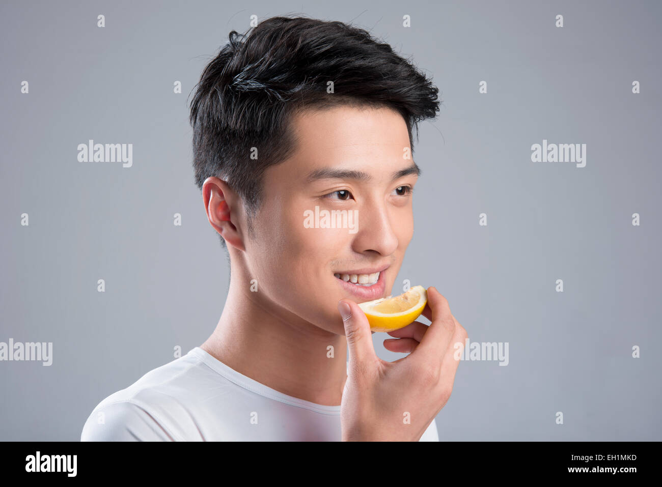 Young man eating lemon Stock Photo - Alamy