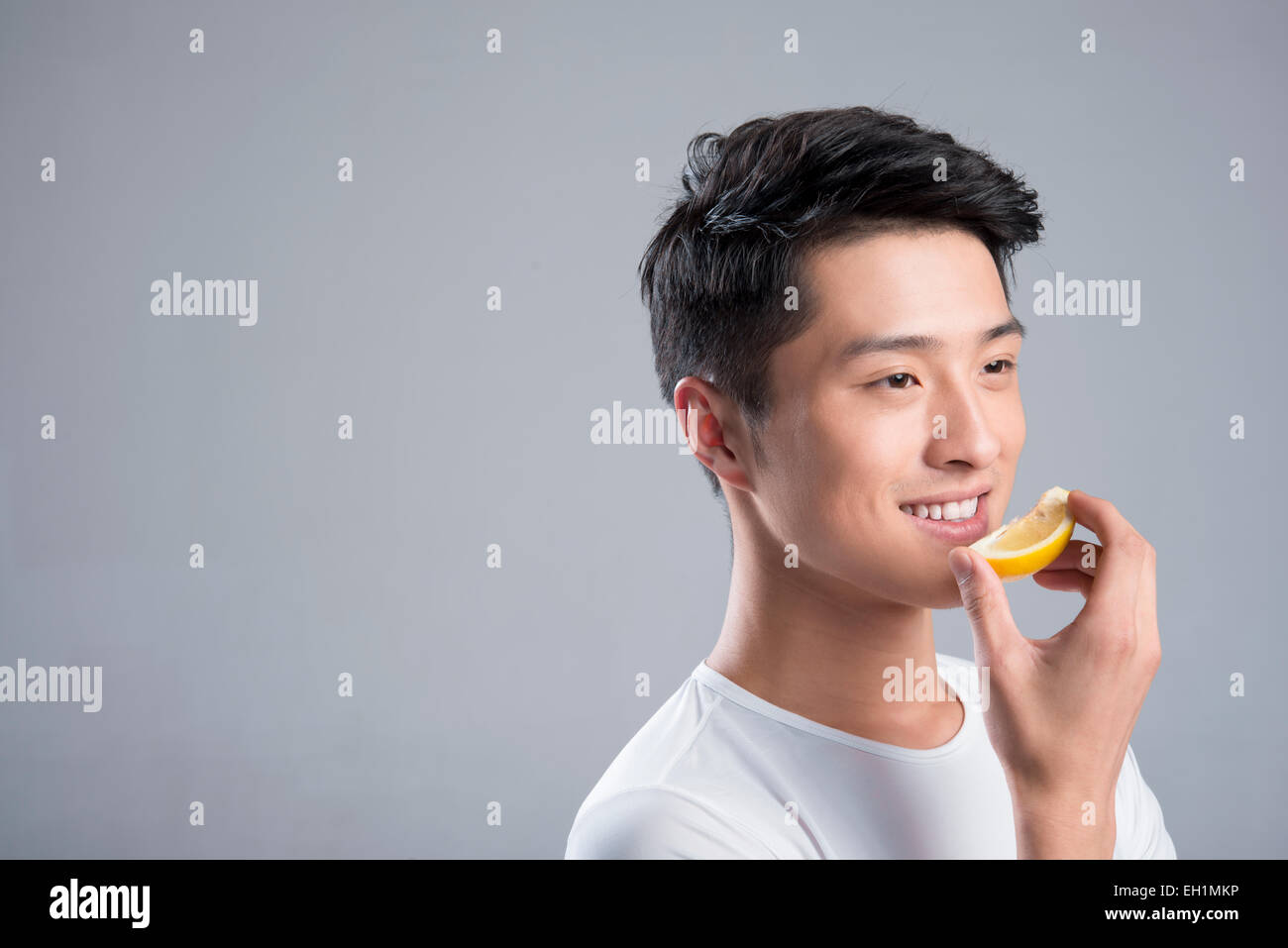 Young man eating lemon Stock Photo - Alamy