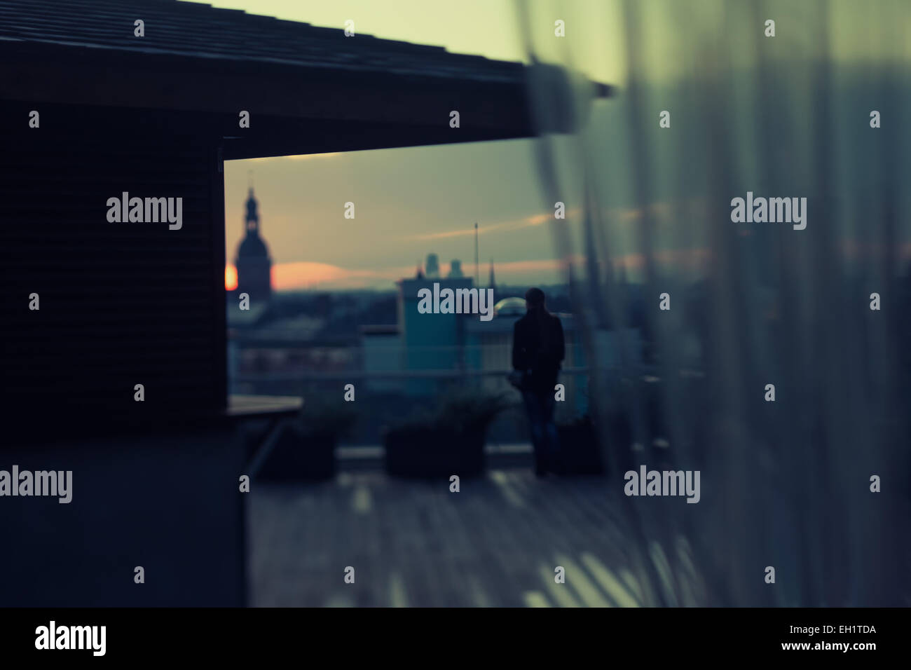 Lonely girl in an empty cafe on the roof of the house in Riga in the ...
