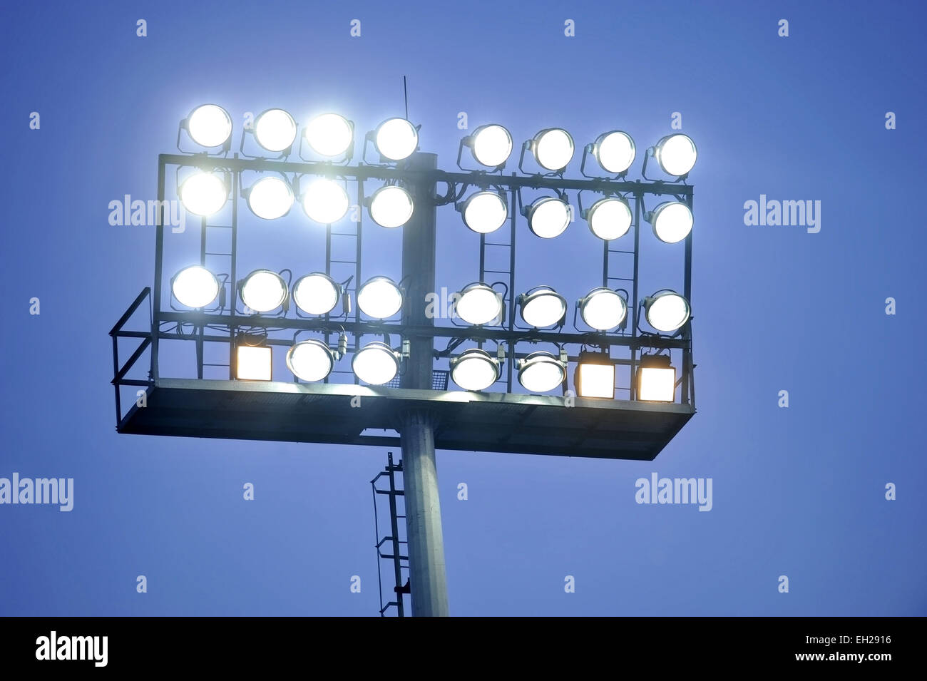 Football stadium spotlights turned on at sunset Stock Photo - Alamy