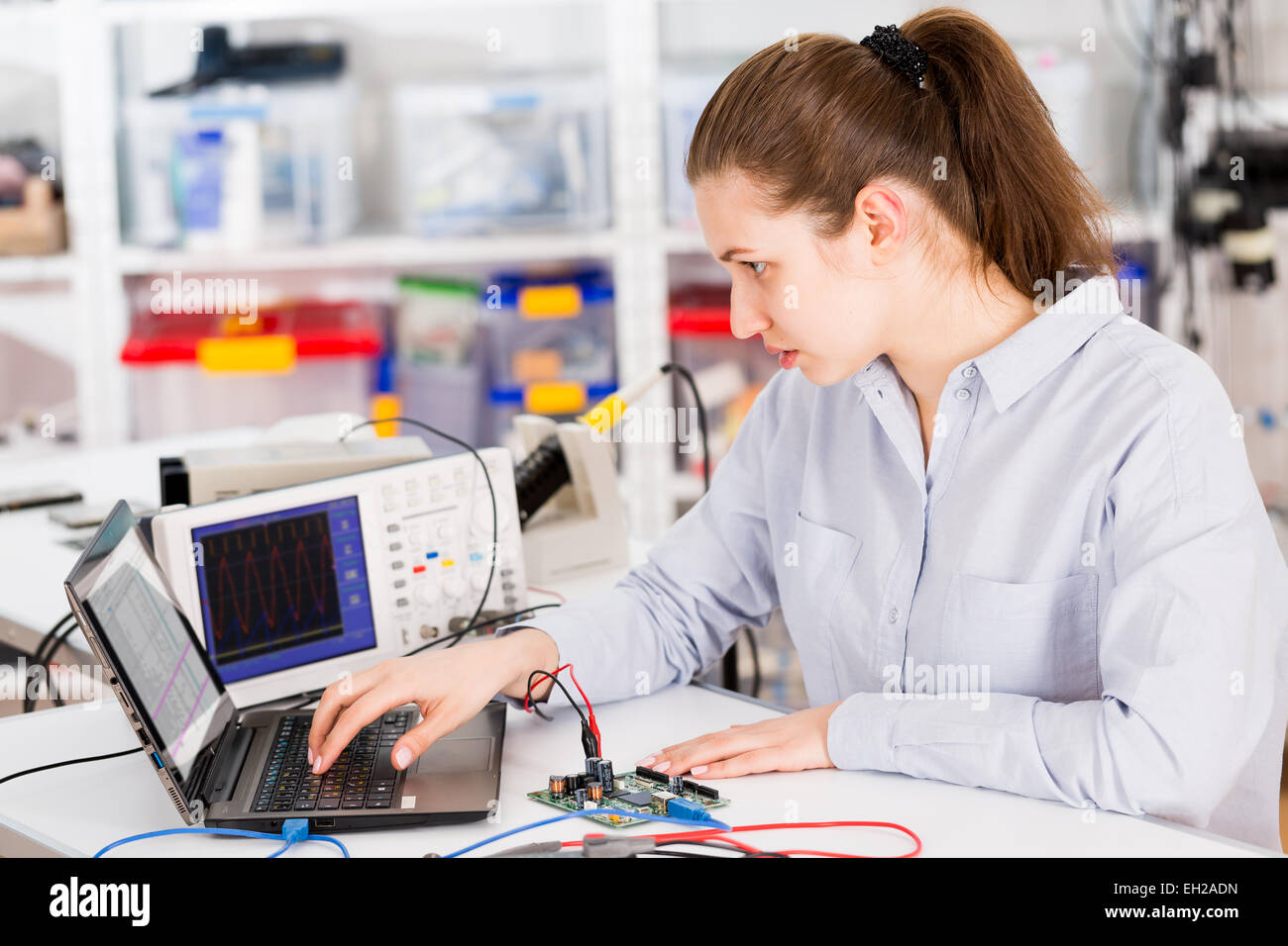 Woman with a tester and a printed circuit board Stock Photo - Alamy