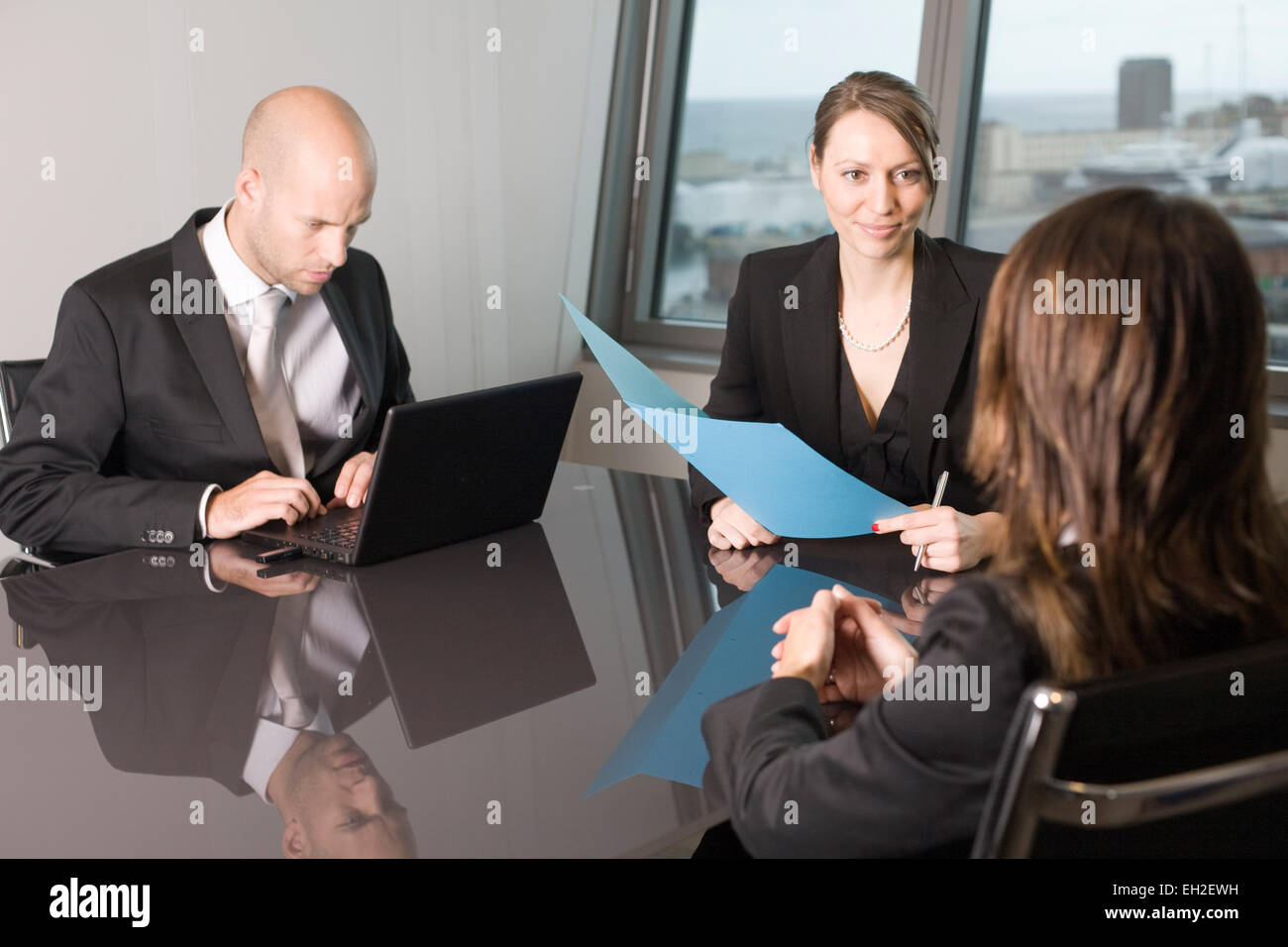 Three persons sitting at a table in office during job interview Stock ...