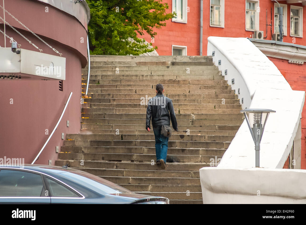young man rises on a granite ladder to the red house Stock Photo - Alamy