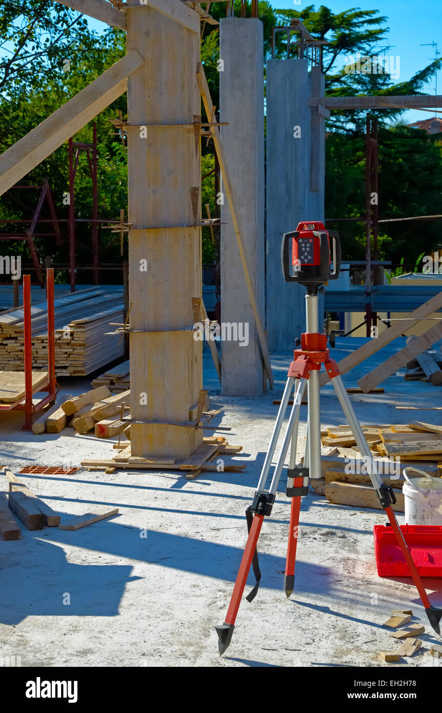Electronic level on a tripod set up at a construction site, with ...